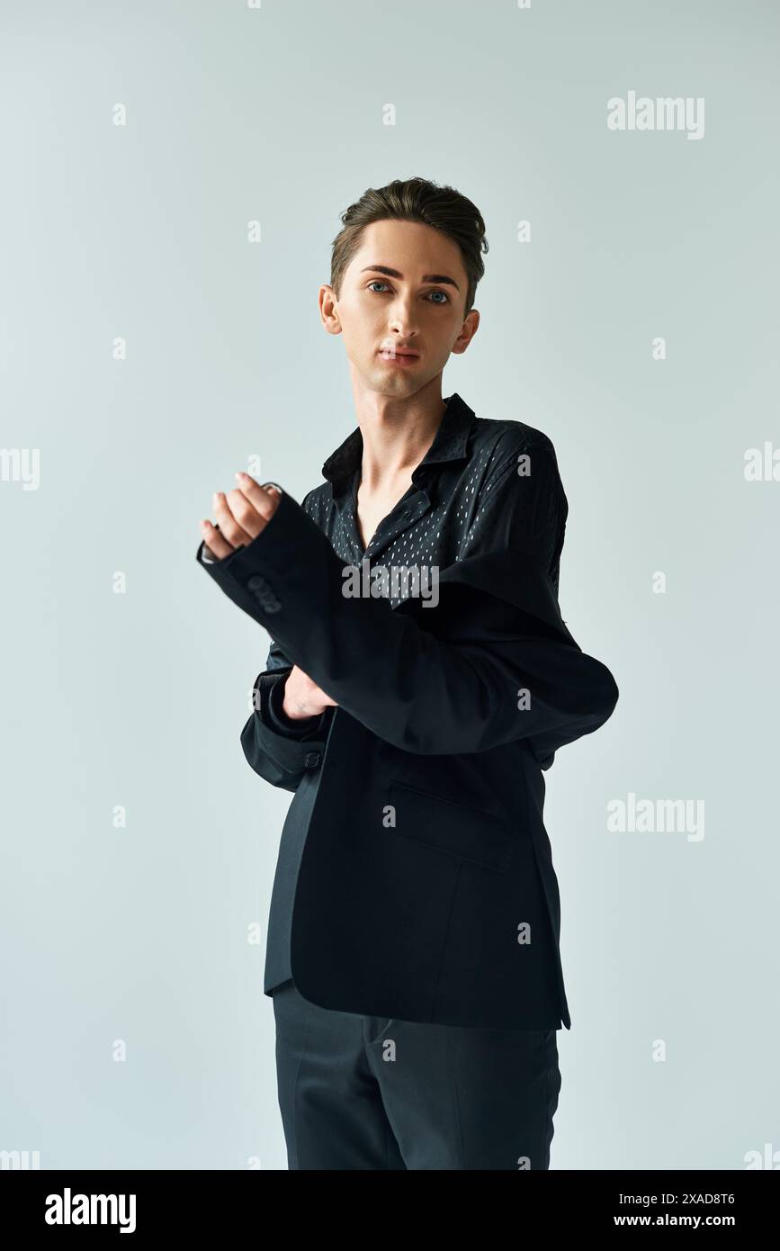 A young queer man in a sleek black suit strikes a confident pose ...