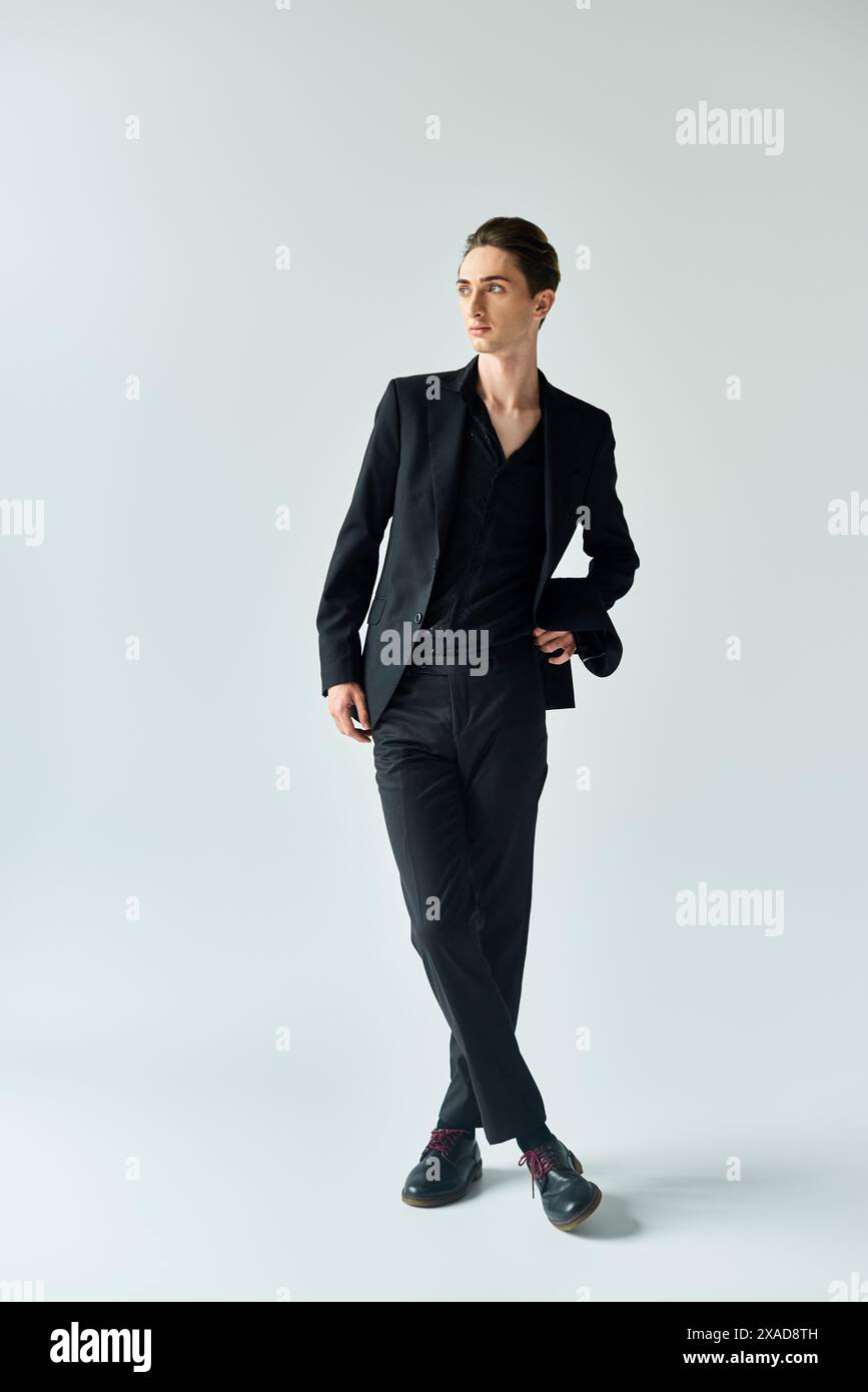 A young queer man, dressed in a sleek black suit, confidently poses for ...