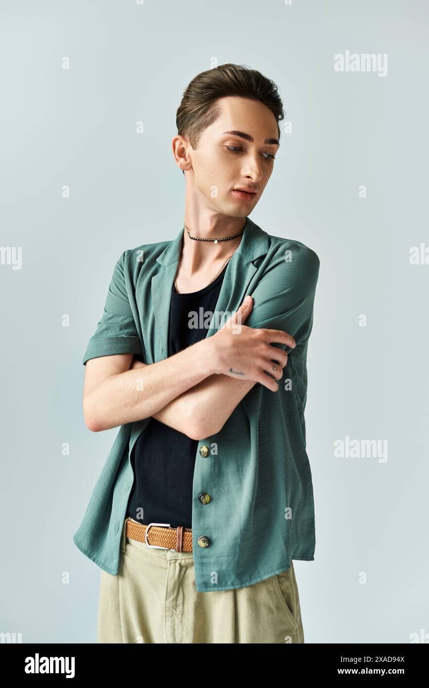 A young queer person confidently poses in a studio wearing a green ...
