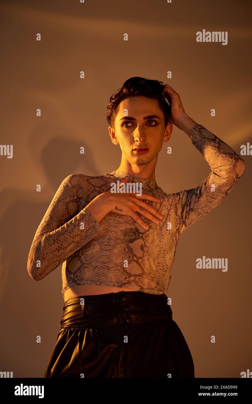 A young queer man with tattoos strikes a confident pose, hands on hips ...