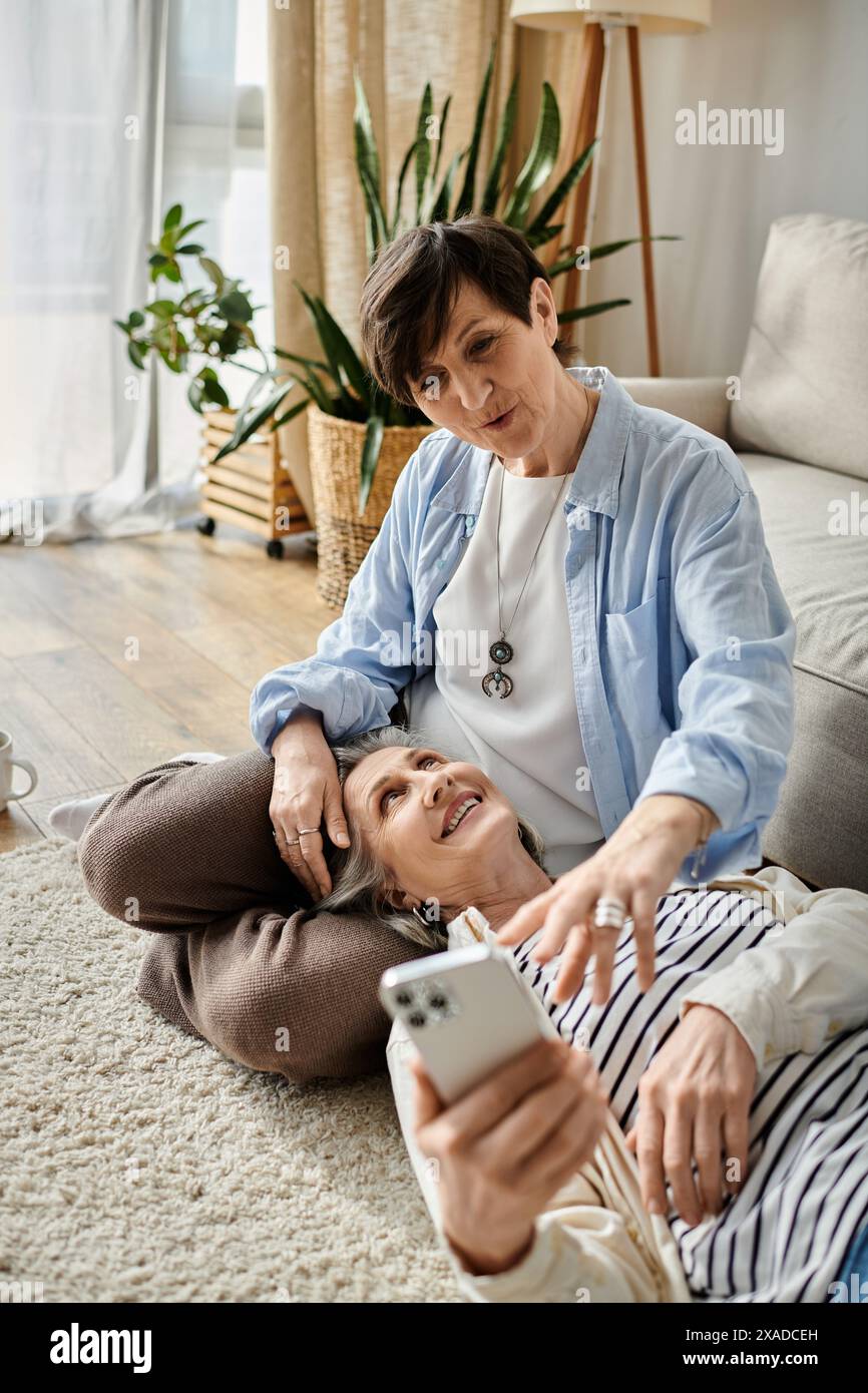 Two women reclining, gazing at smartphone screen Stock Photo - Alamy