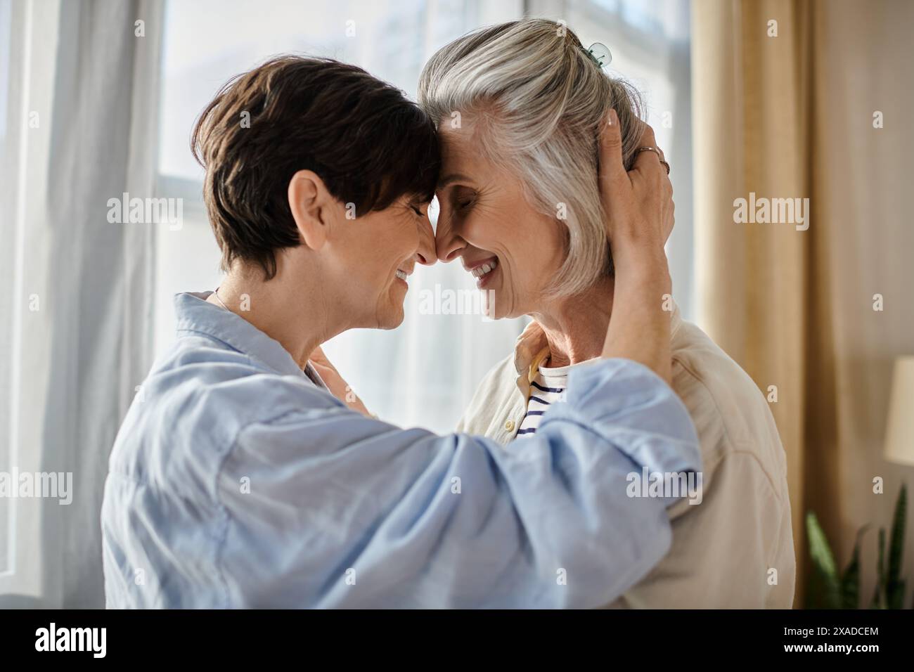 Two older women embrace lovingly in front of a window Stock Photo - Alamy