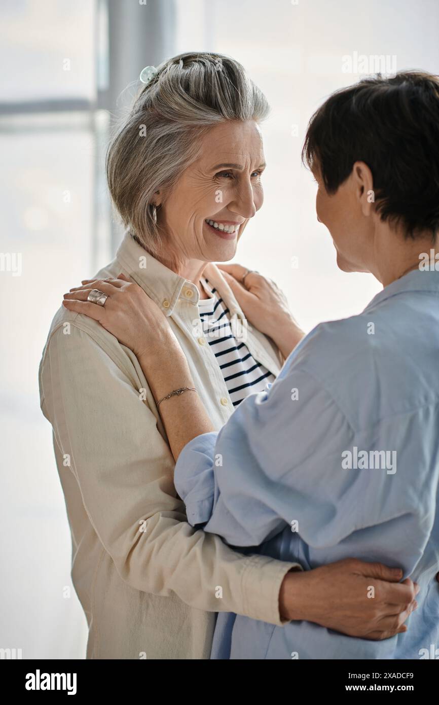 Two women, mature and loving, hugging by a window Stock Photo - Alamy