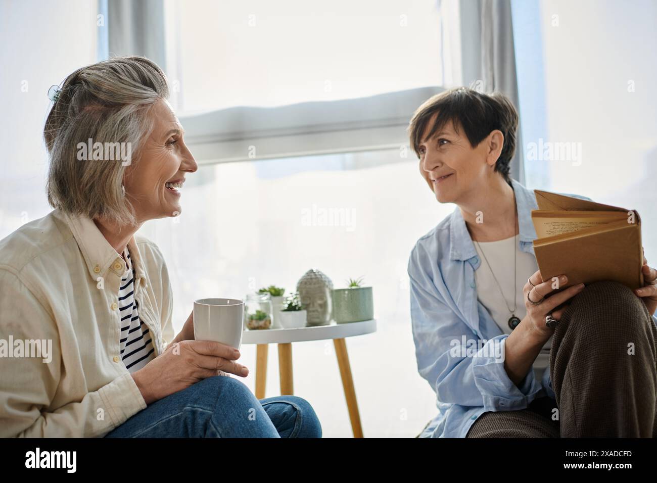 Two older women engaged in a lively conversation on a couch Stock Photo ...
