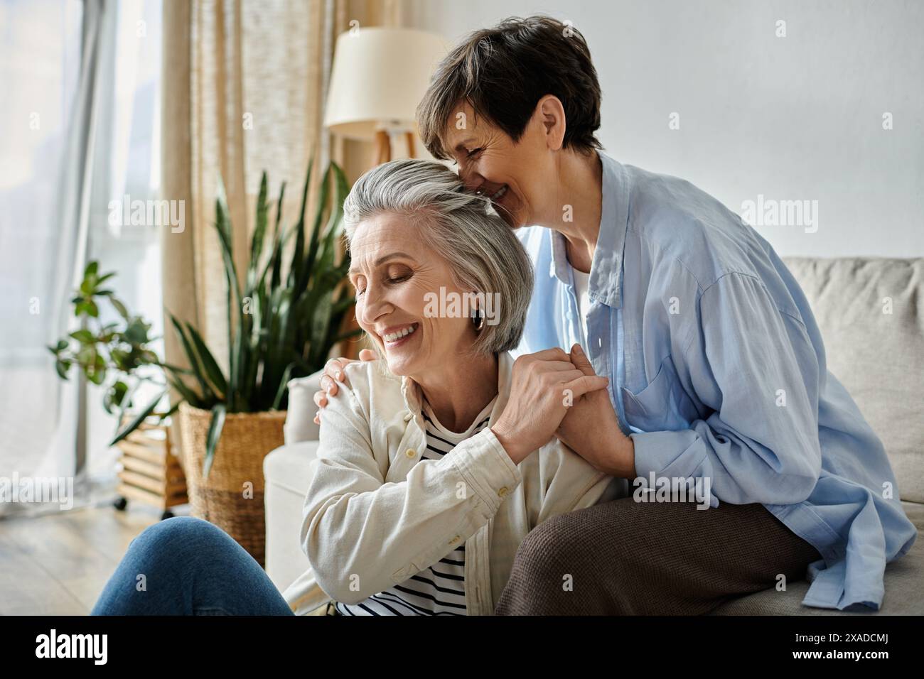 Two elderly women hugging tenderly on a cozy couch Stock Photo - Alamy