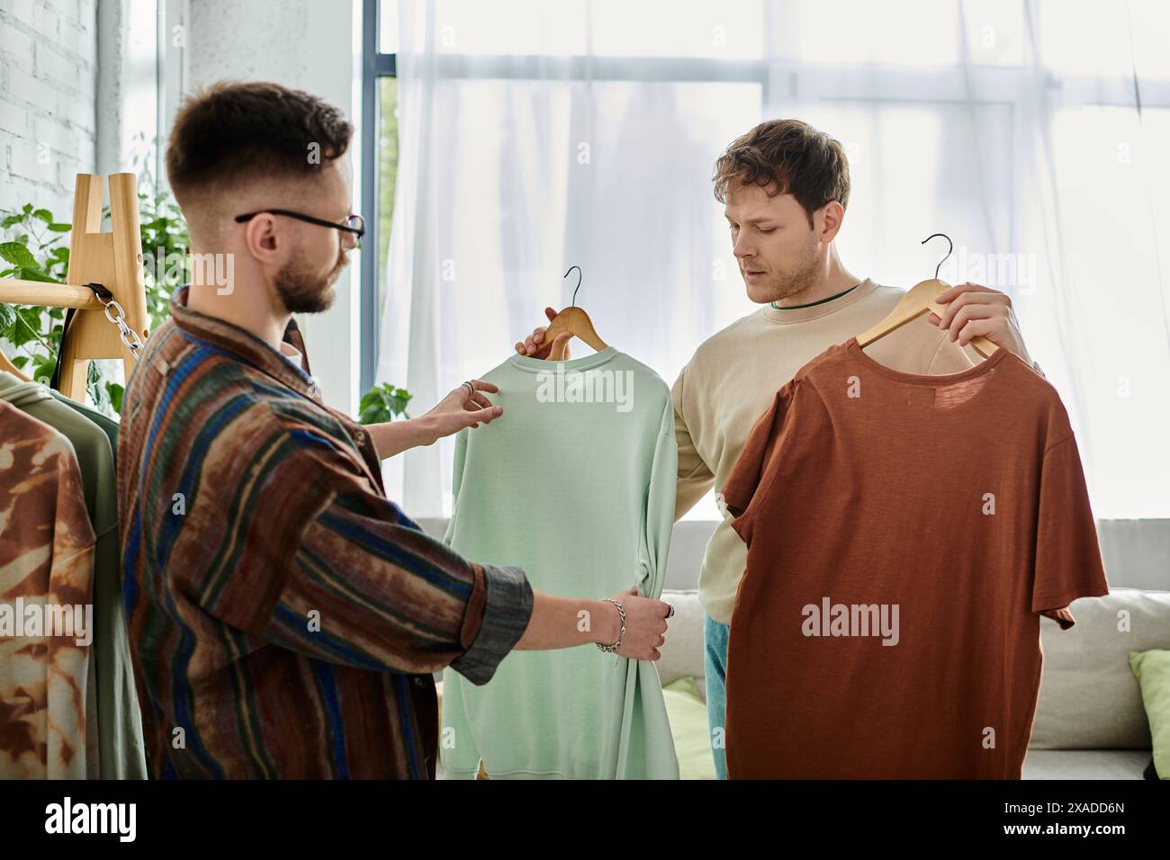 Two men, a gay couple, stand side by side in a designer workshop, working on creating trendy ...
