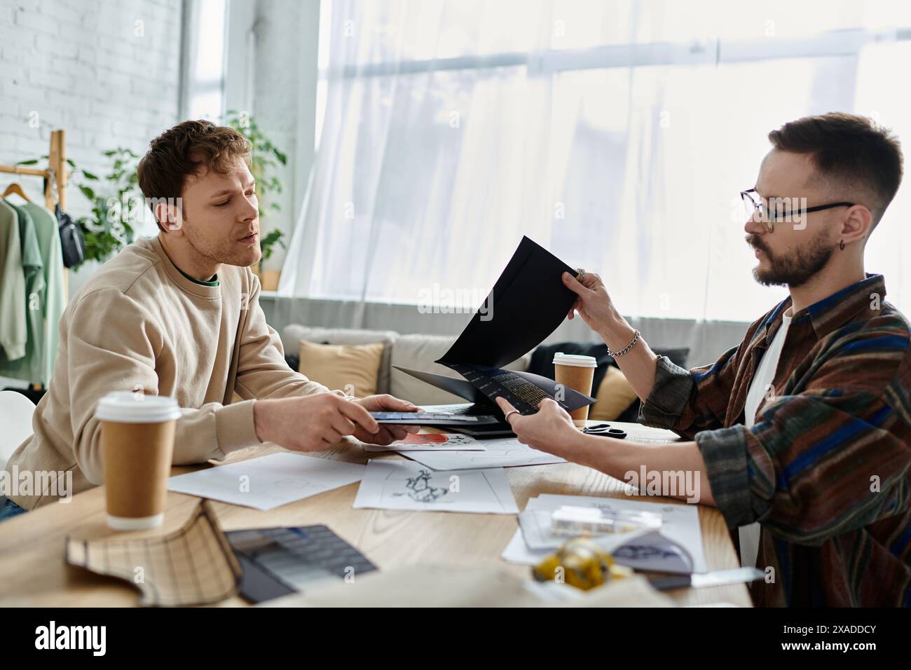 Two men in a designer workshop, working on papers and laptop, crafting ...