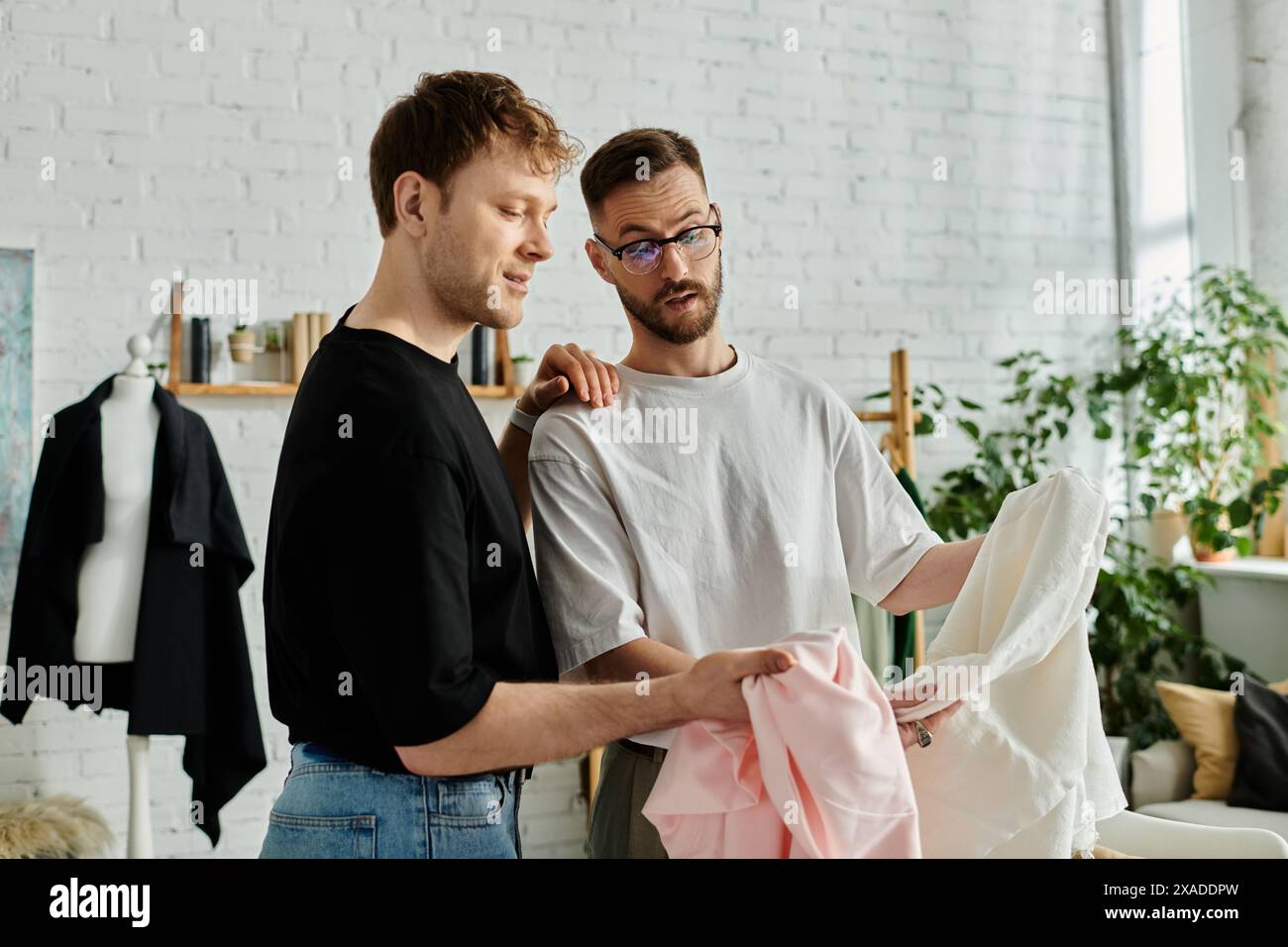 Two men, a gay couple, stand side by side in a designer workshop, collaborating on trendy attire ...