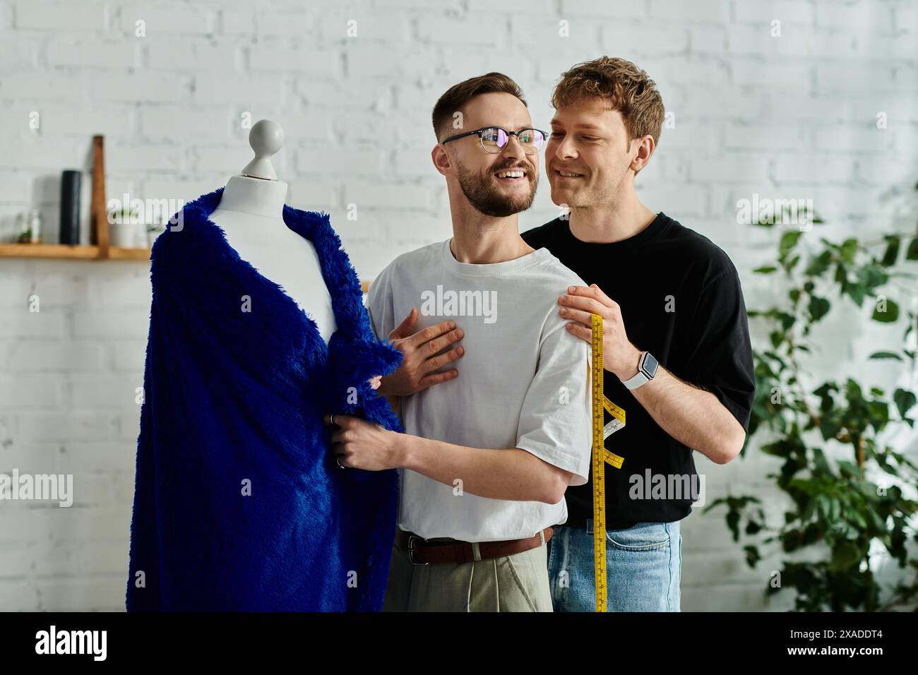 Two male designers standing beside a dress on a mannequin in a creative ...