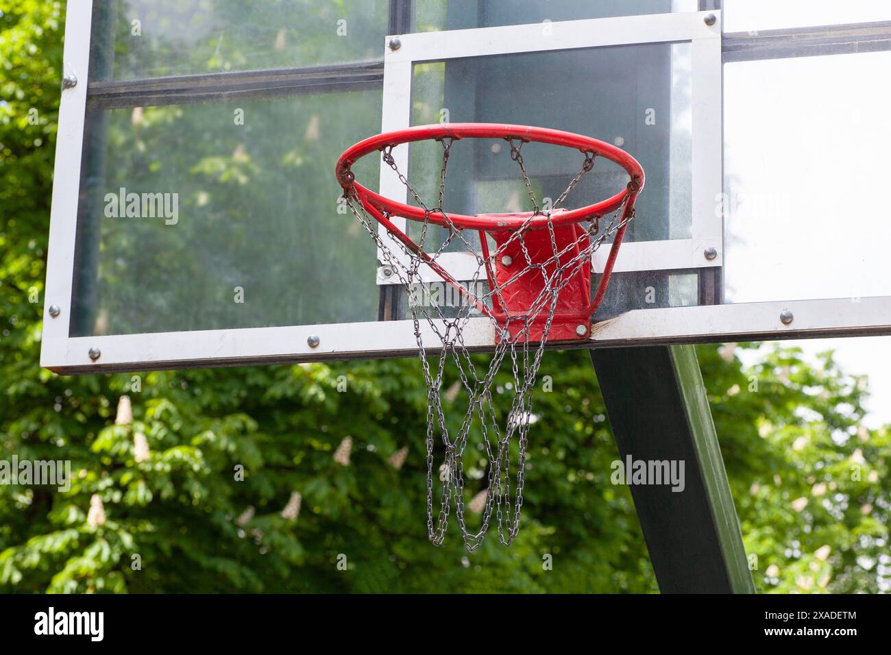 Basketball hoop with red rim and chain net on an outdoor court, framed ...