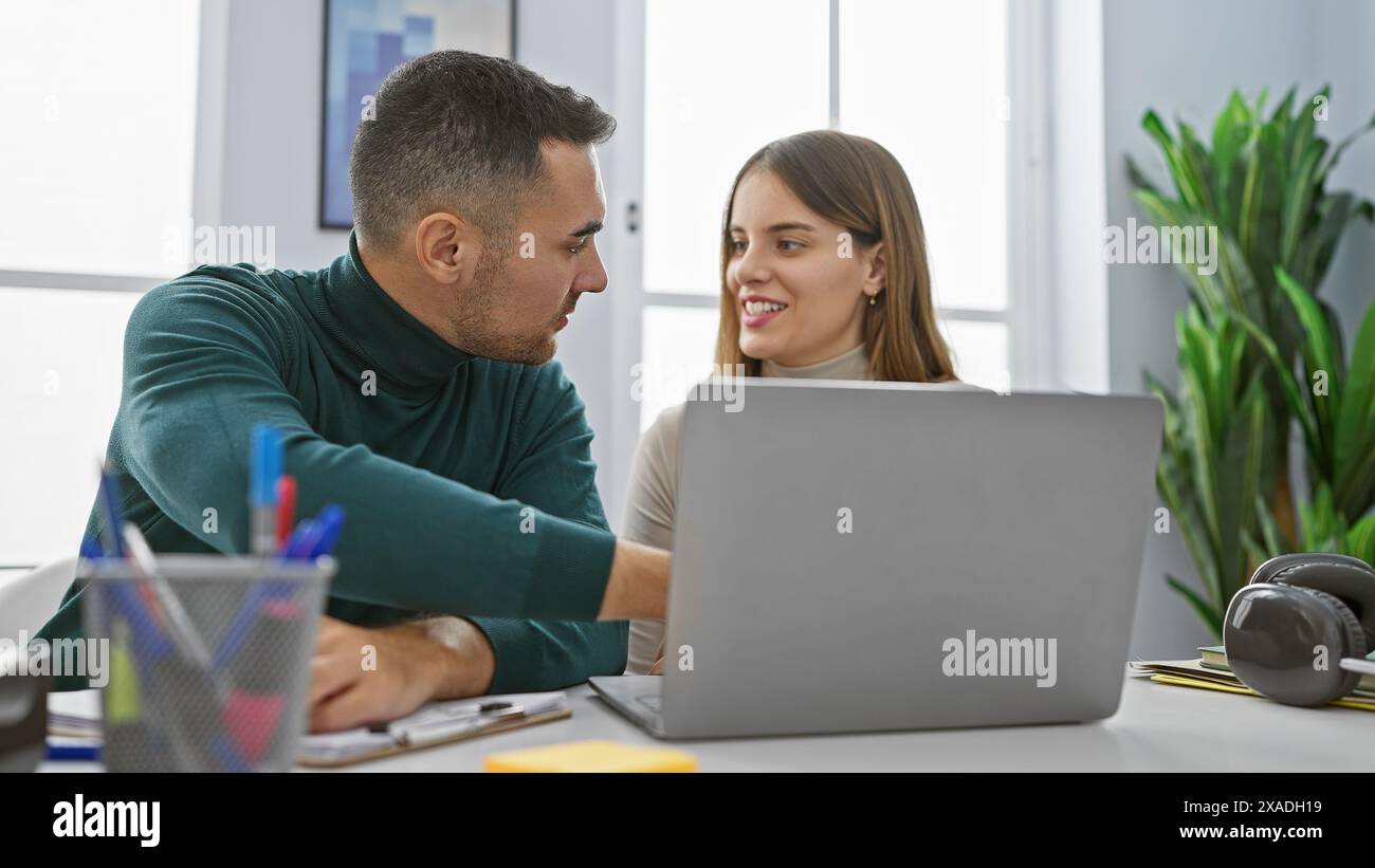 A man and woman engage as colleagues at a modern office, working ...