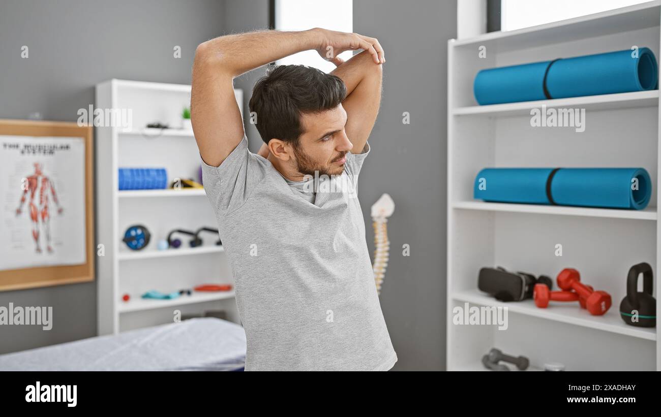 Handsome young man stretching in a modern rehabilitation clinic with ...