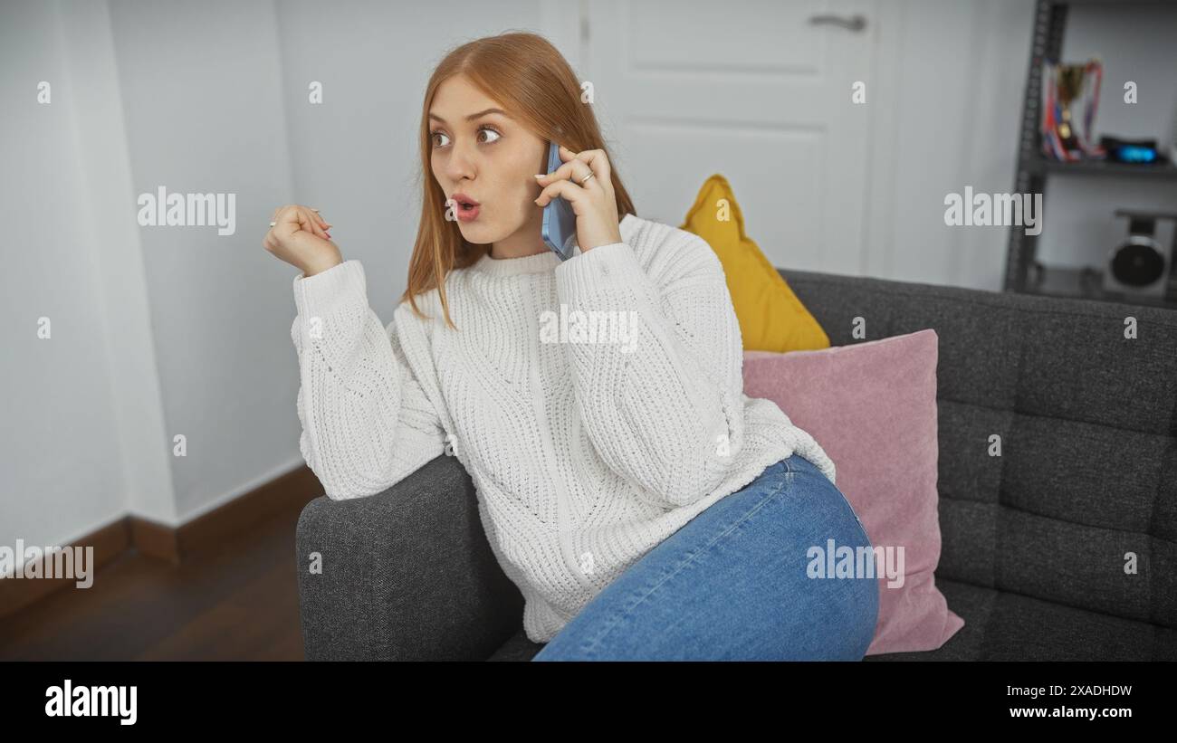 A surprised young woman talks on the phone in a cozy living room ...