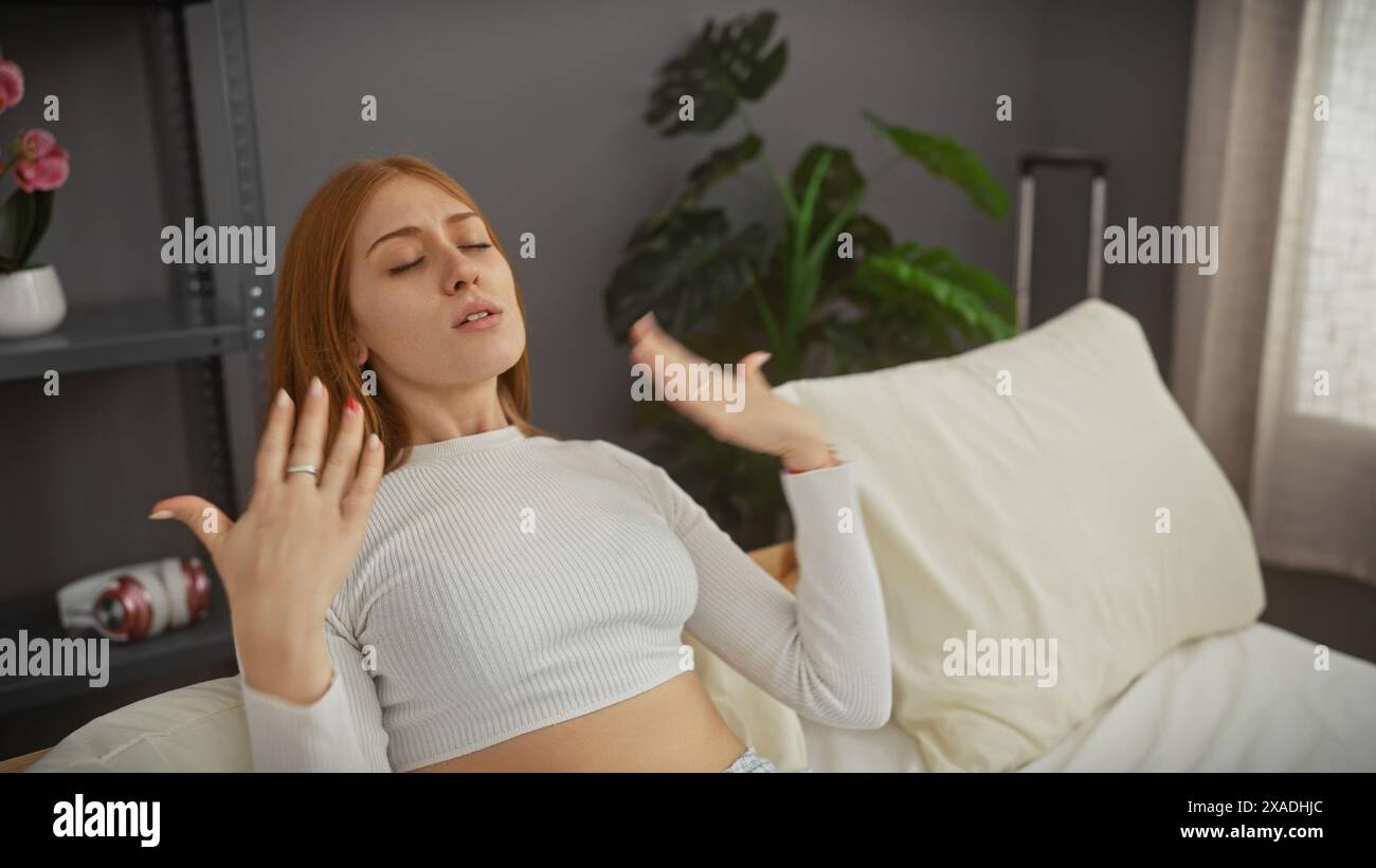 A young woman cooling herself in a modern bedroom setting, conveying a ...