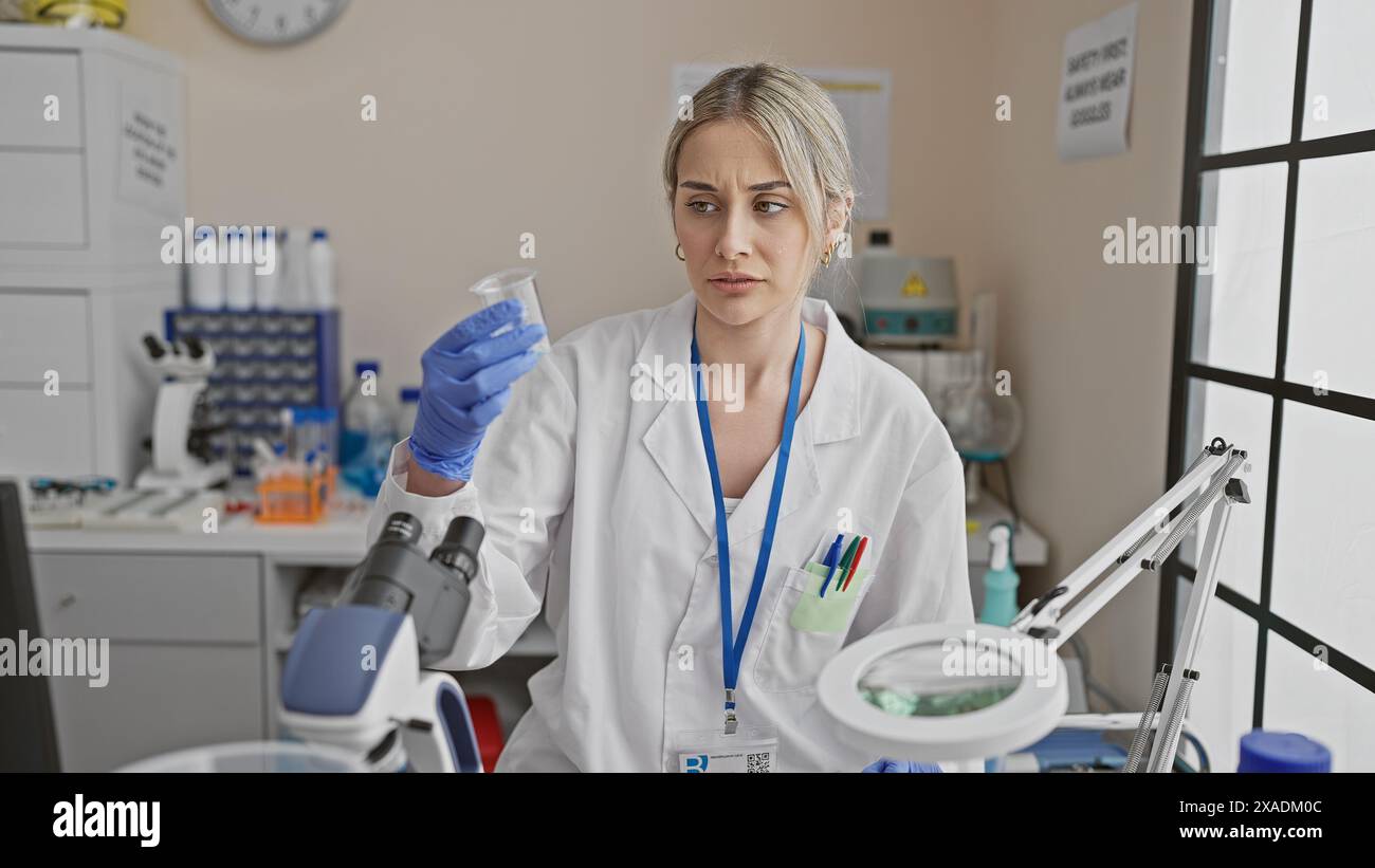 Focused young woman scientist analyzing a specimen in a modern ...