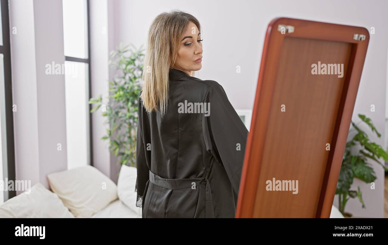 Elegant woman in black examining her reflection in bedroom mirror ...