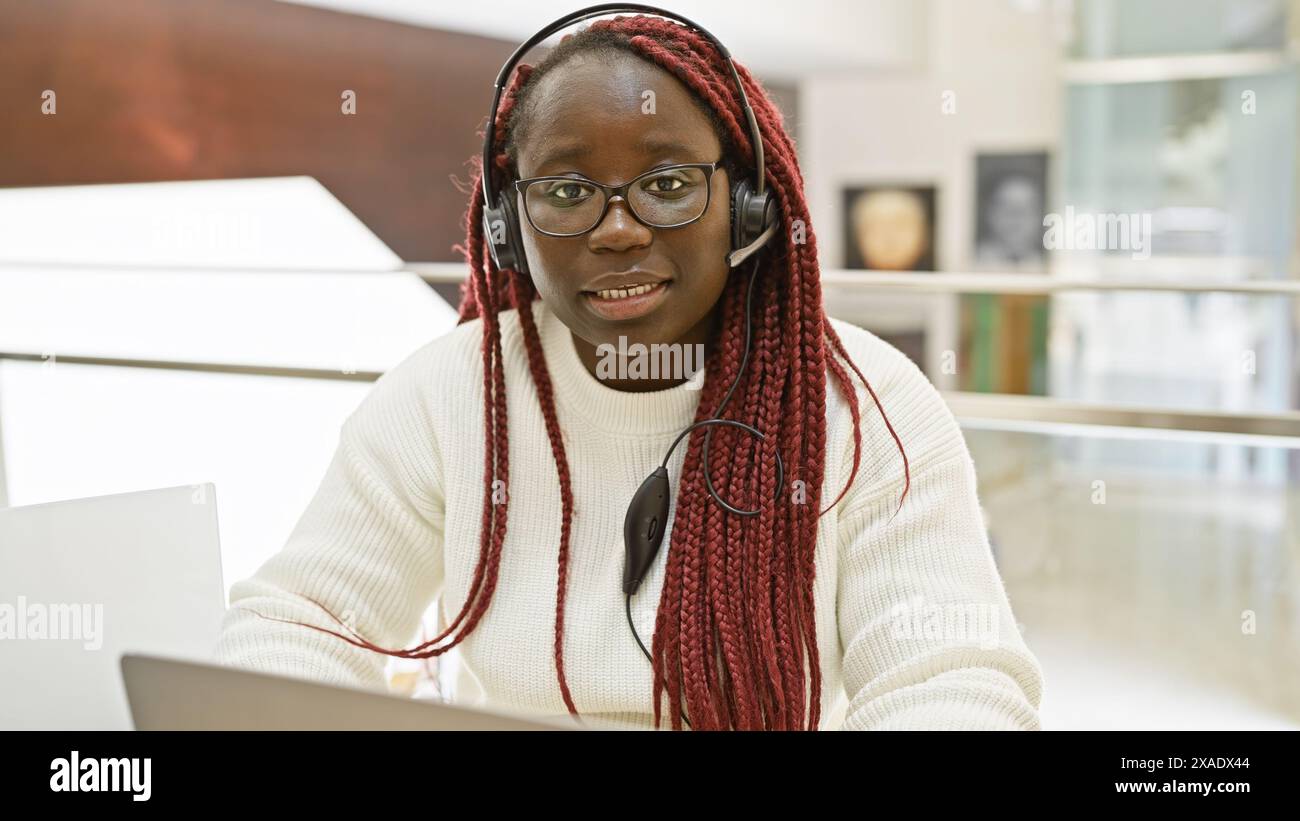 Professional african woman with braids wearing headset in indoor office ...