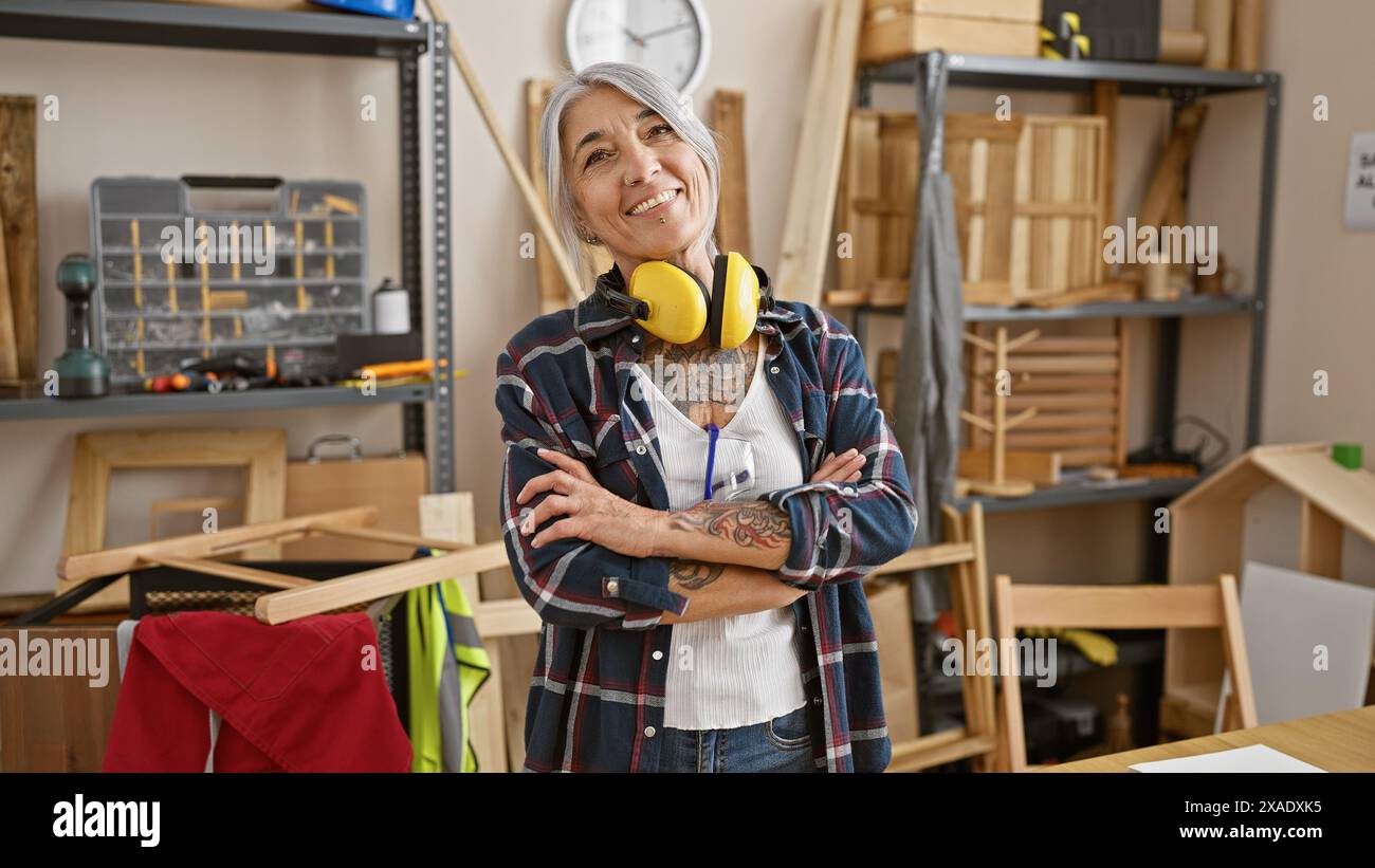 Beautiful, mature carpenter lady standing at her indoor woodwork studio ...