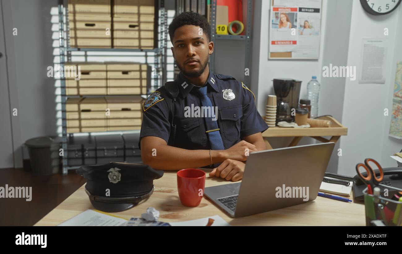 Handsome african american male police officer working on laptop in an ...