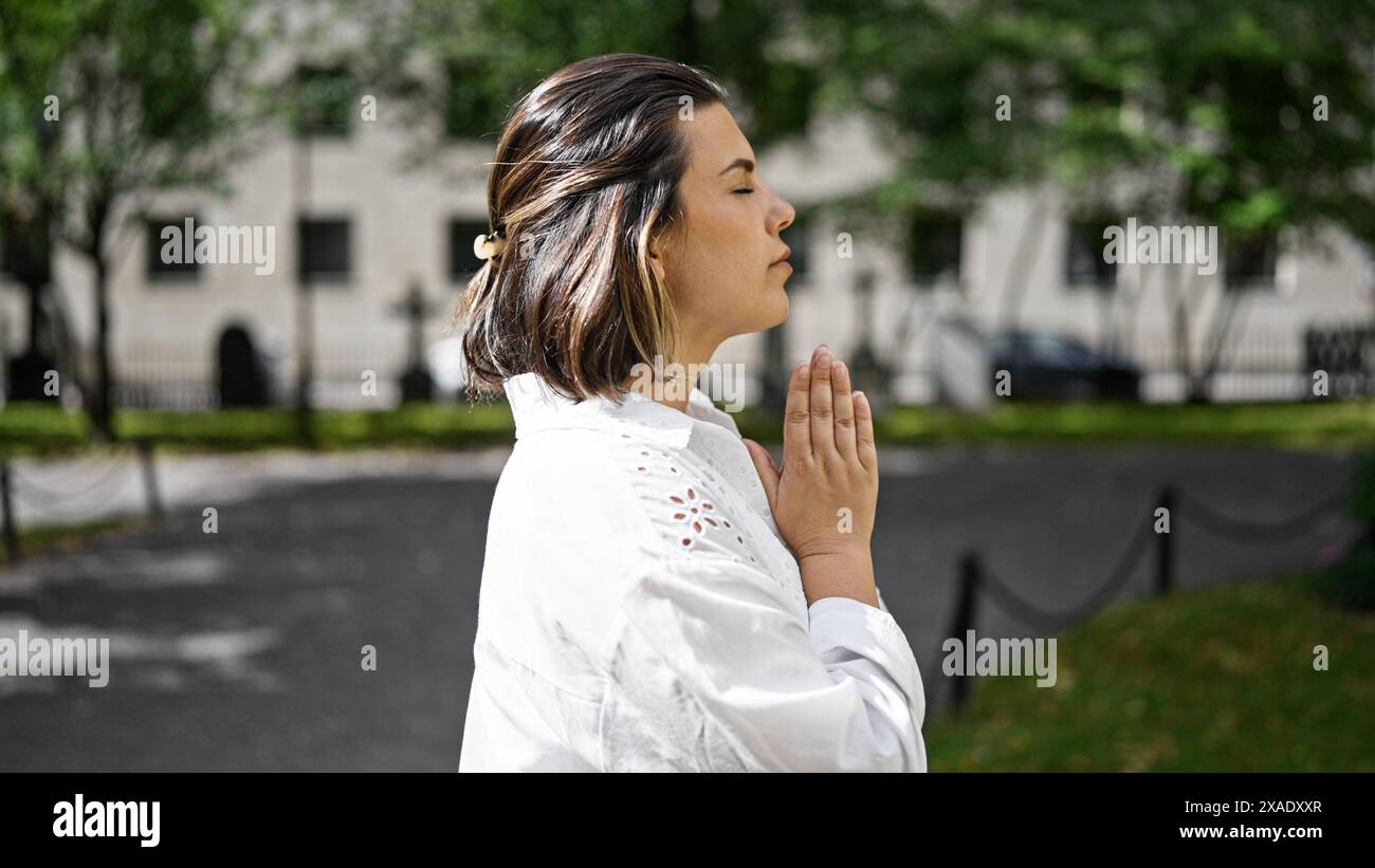 Beautiful young hispanic woman praying and mourning by tombstone at ...