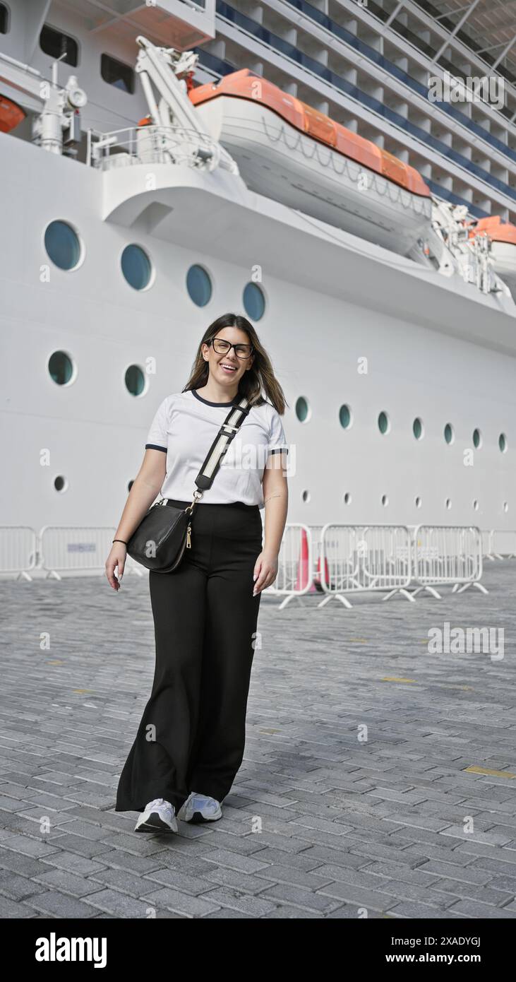 A smiling young adult woman enjoys a luxury cruise vacation, strolling ...