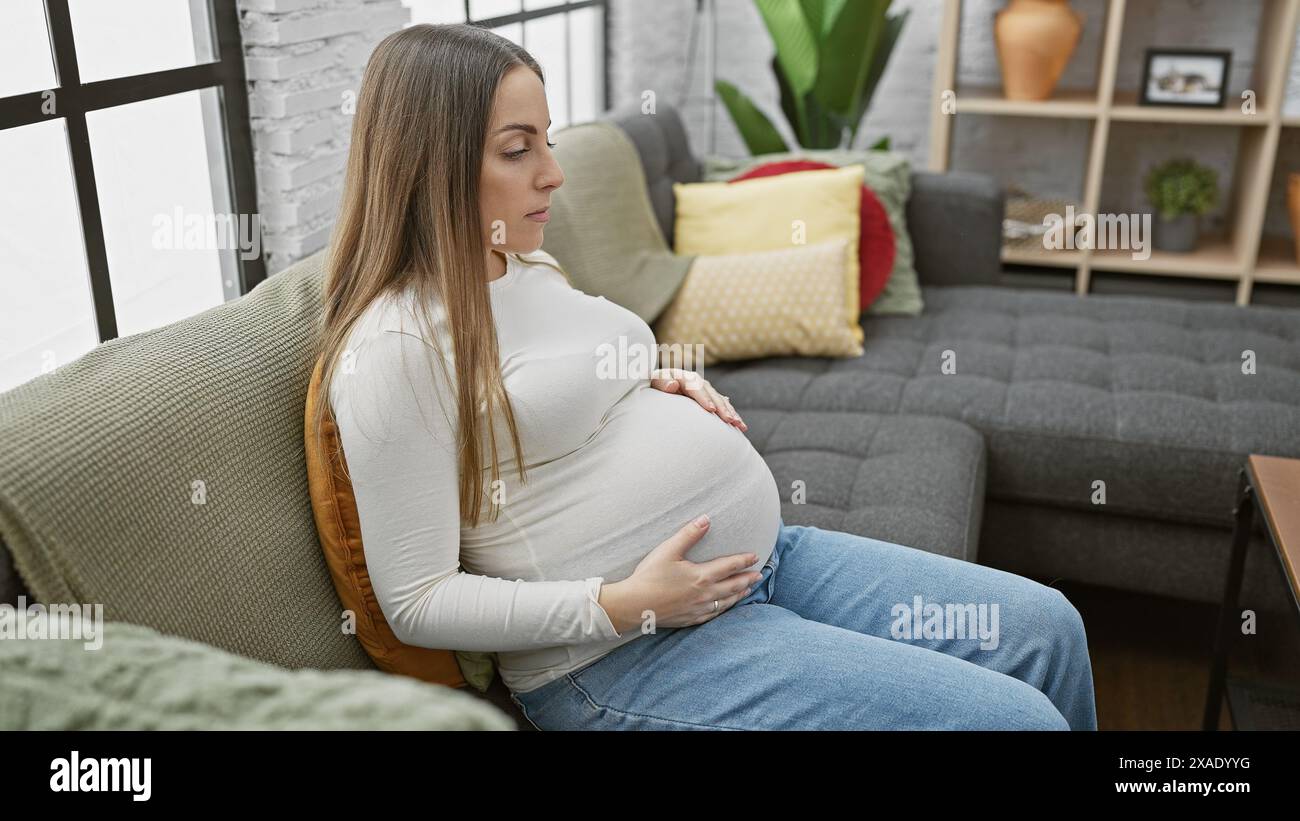 A thoughtful pregnant hispanic woman sitting comfortably indoors ...