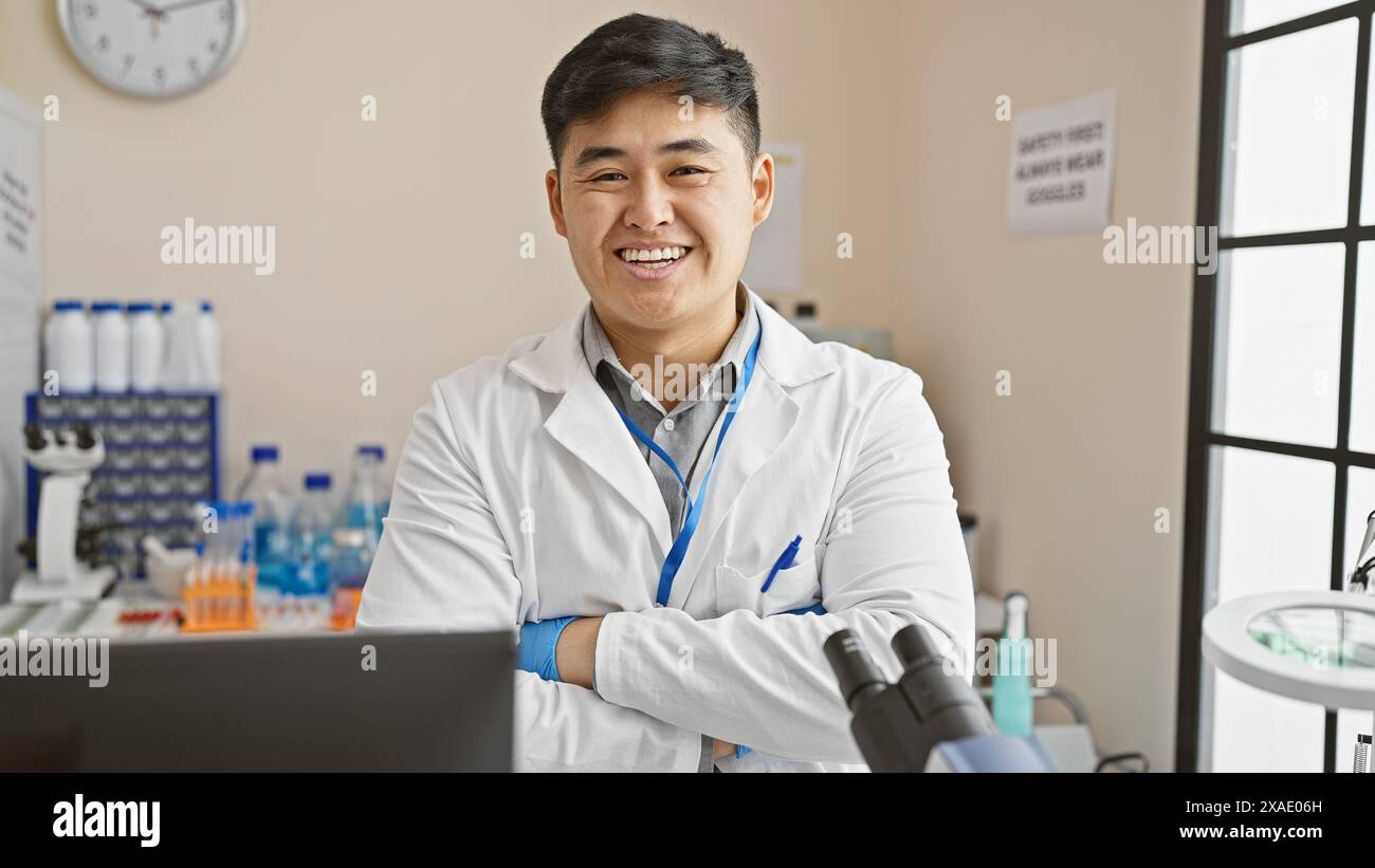 Smiling asian man in lab coat posing in a modern laboratory with ...