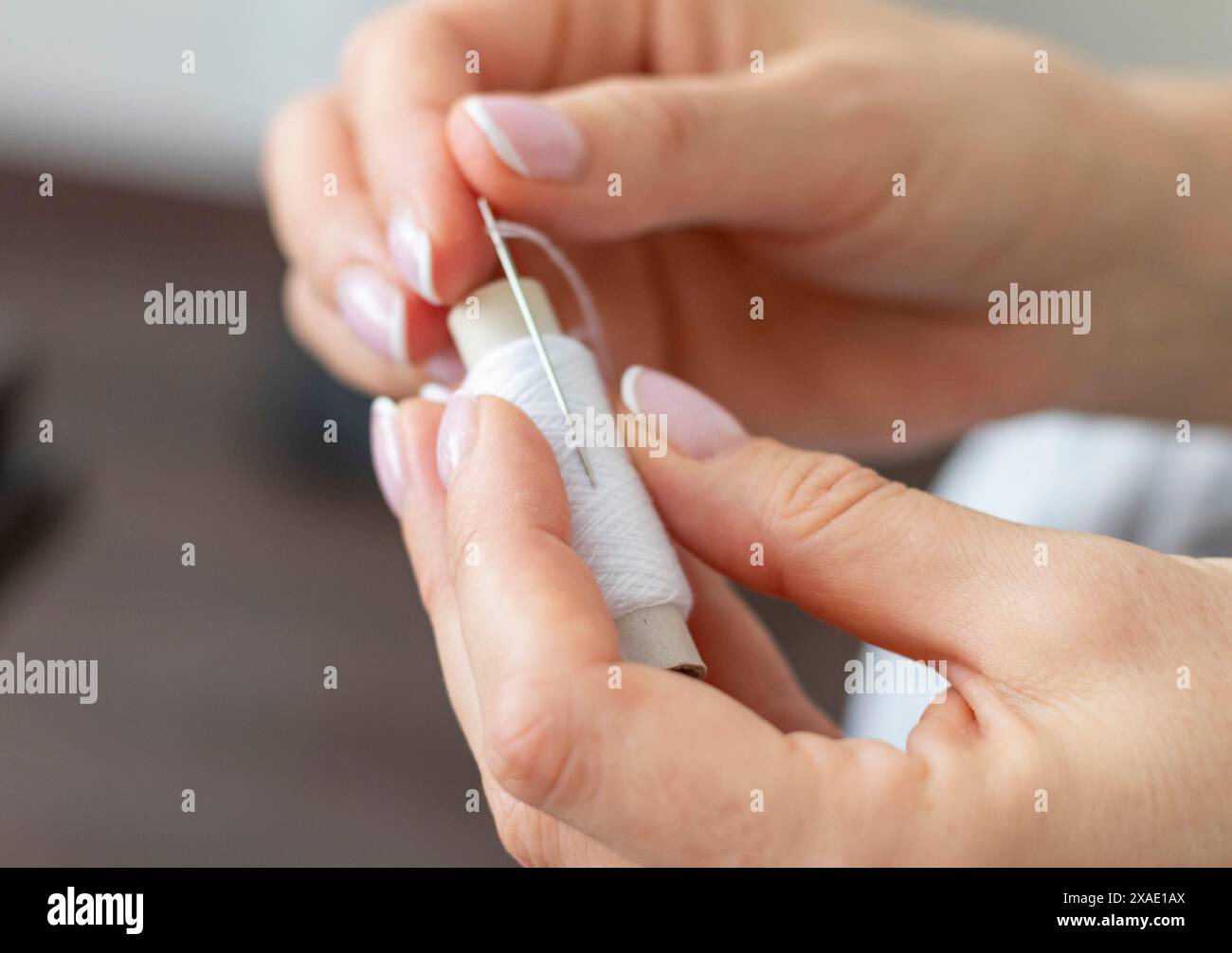 Shot of the woman with beautiful hands stitching up or patching a linen ...