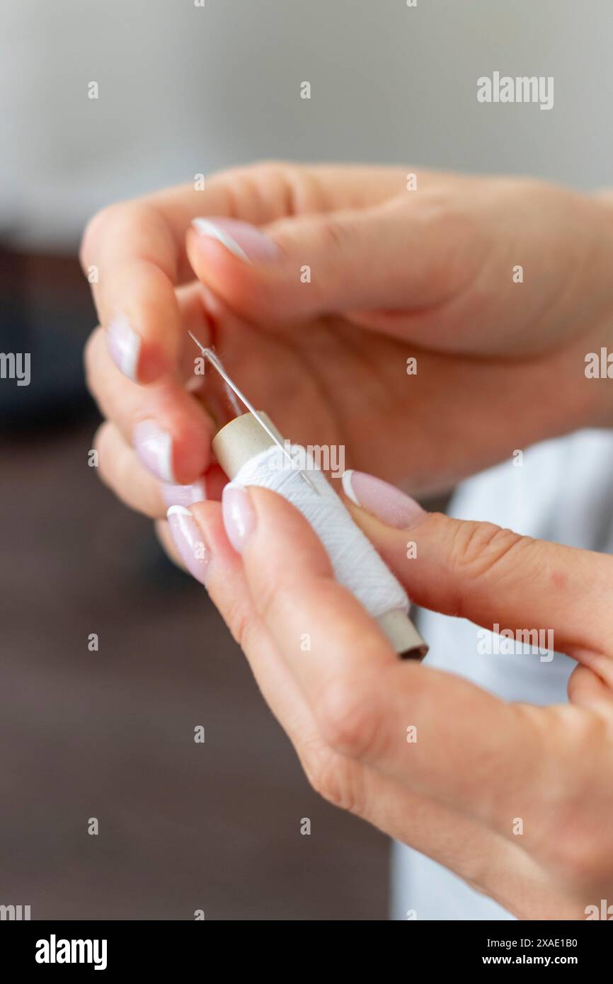 Shot of the woman with beautiful hands stitching up or patching a linen ...
