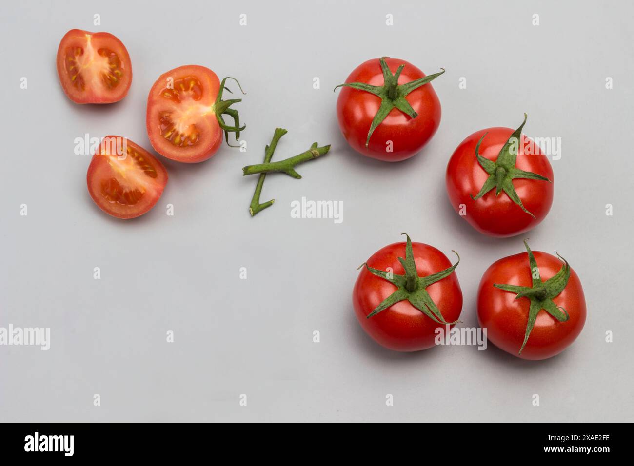 Whole tomato, chopped tomato wedges and scissors. Gray background. Top ...
