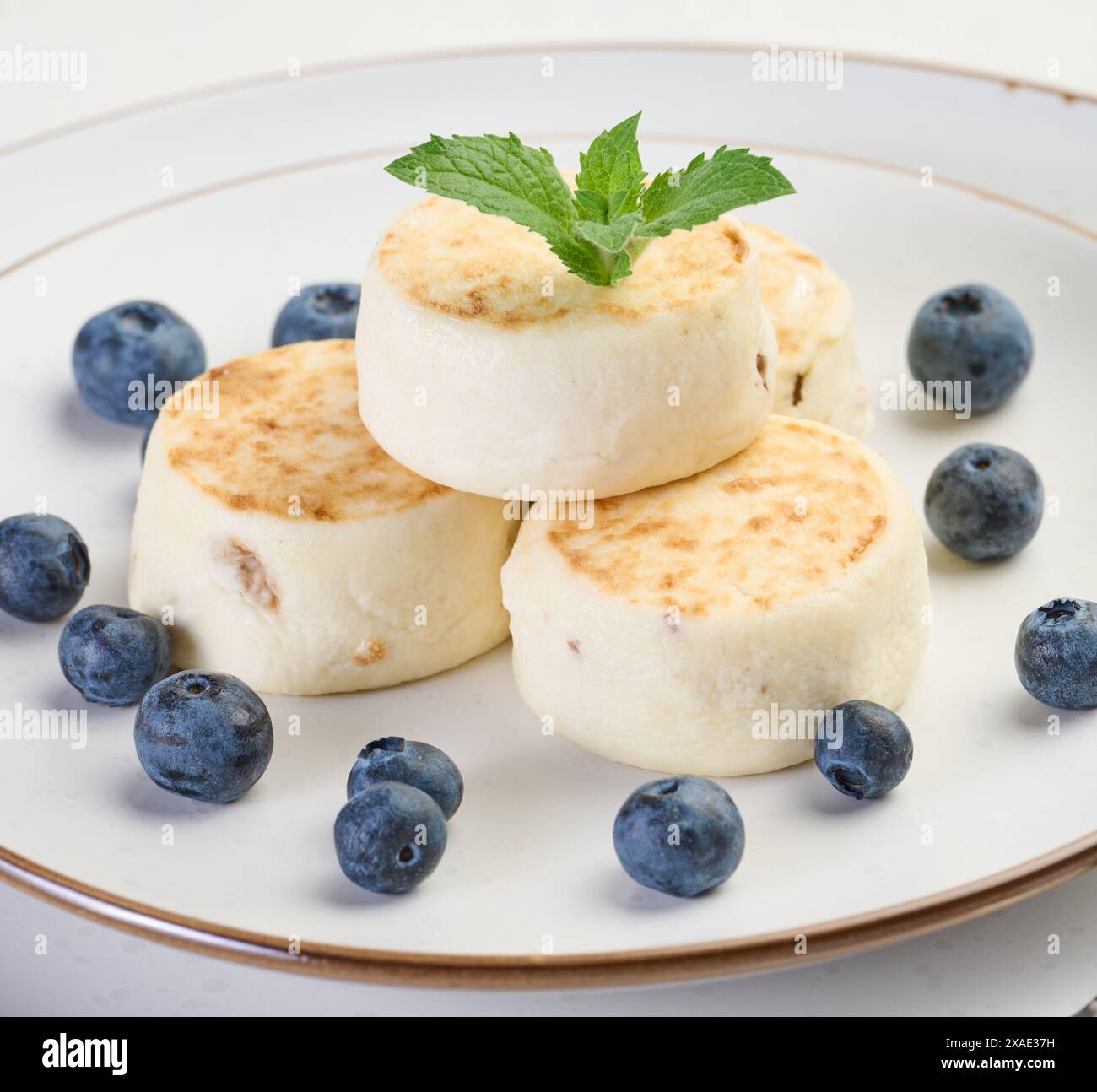 Round small fried cheesecakes on a plate with blueberries. Background ...