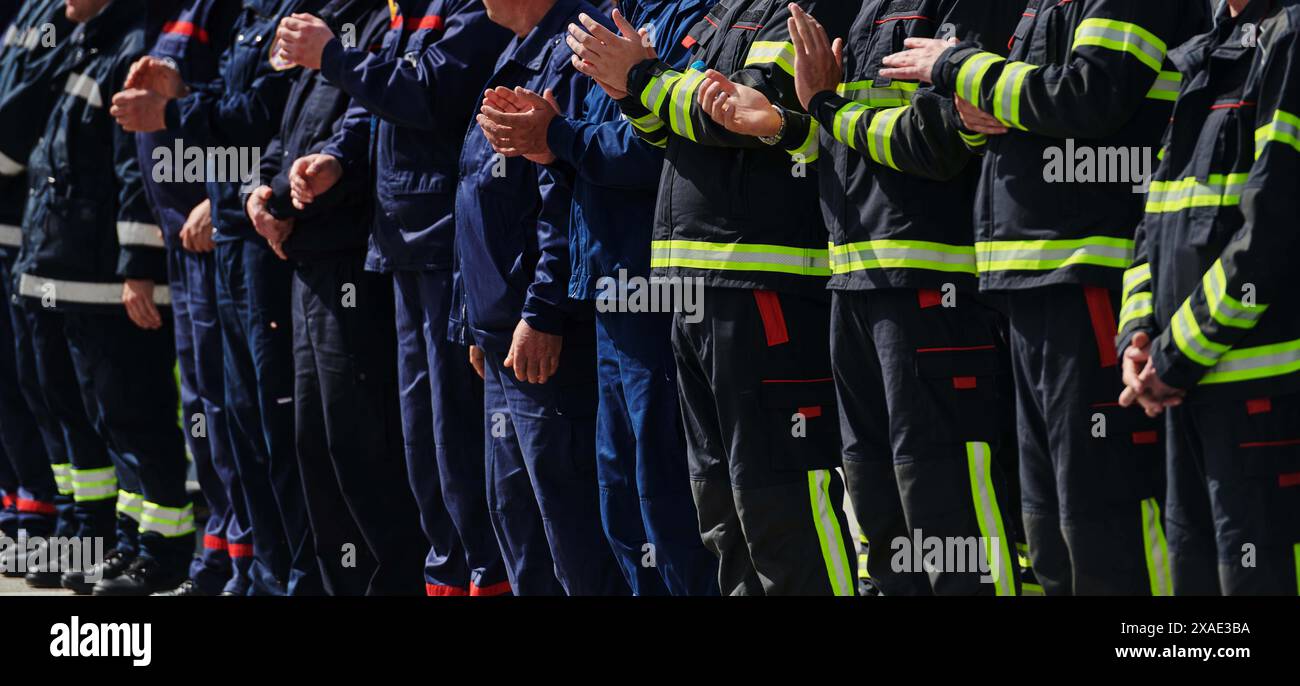 A group of firefighters lined up, saluting the flag, applauding in ...