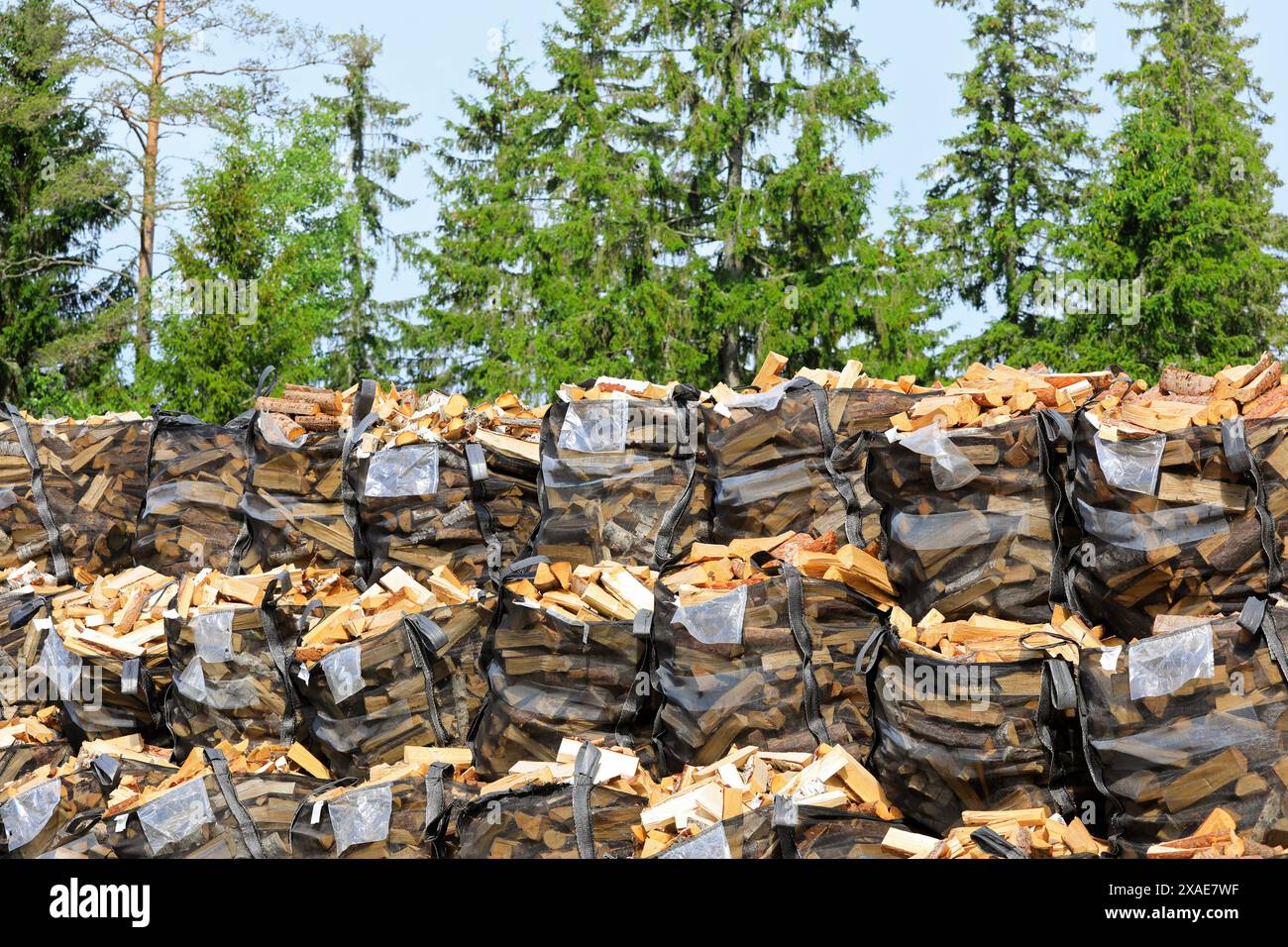 Stacks of cut and split firewood stored in large heavy-duty mesh bags ...