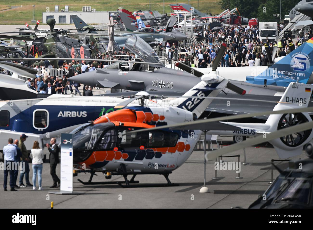 06 June 2024, Brandenburg, Schönefeld: Visitors walk between airplanes and helicopters during ...