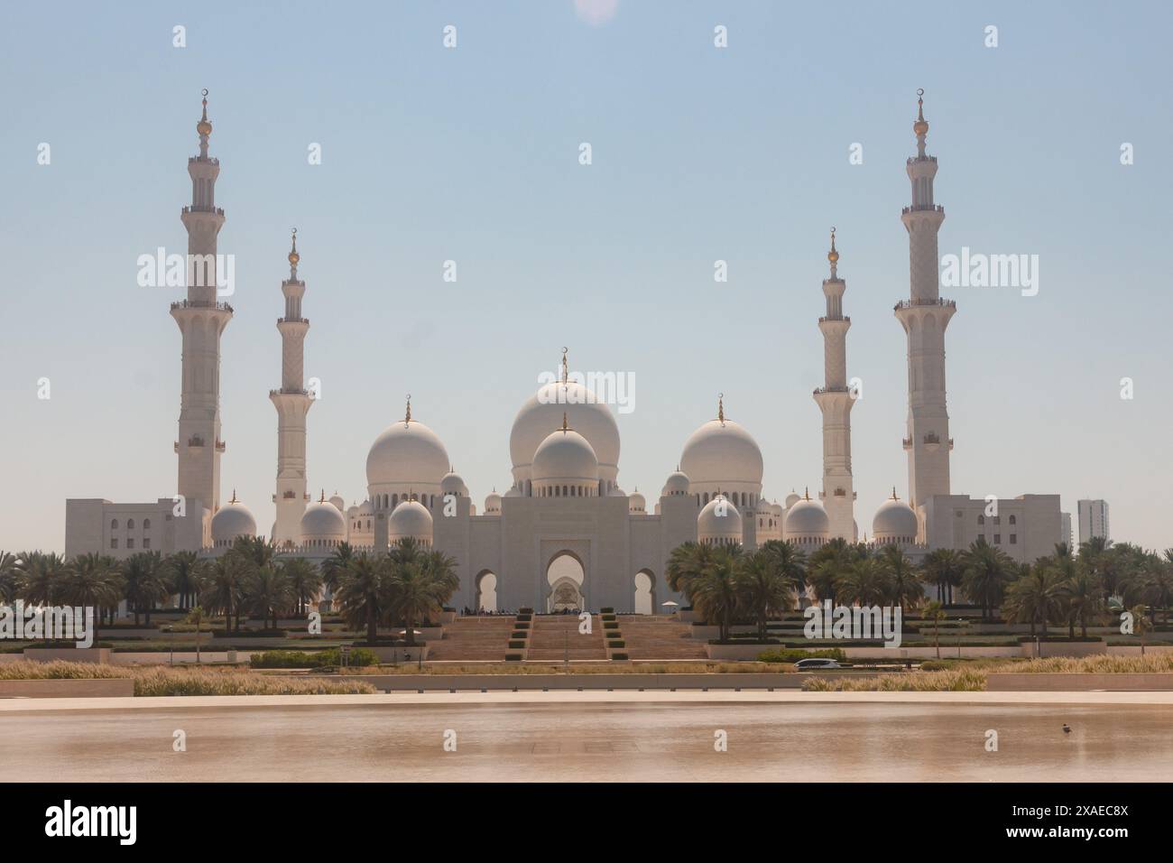 A view of Sheikh Zayed Grand Mosque with palm trees at sunset time ...