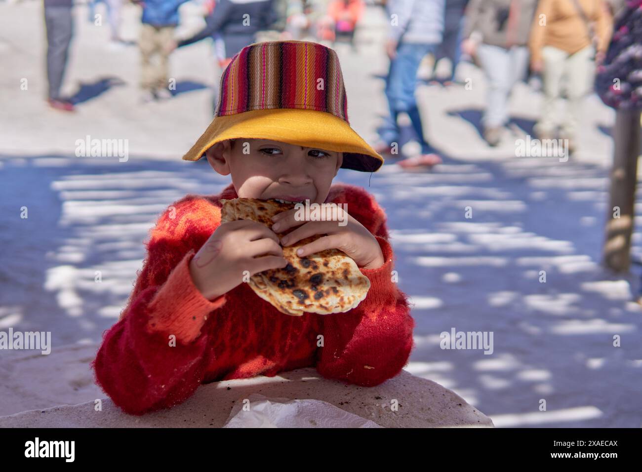 latin boy sitting eating a tortilla asada salteña, typical food from ...