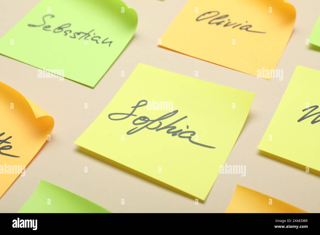 Paper stickers with different names on beige background, closeup ...