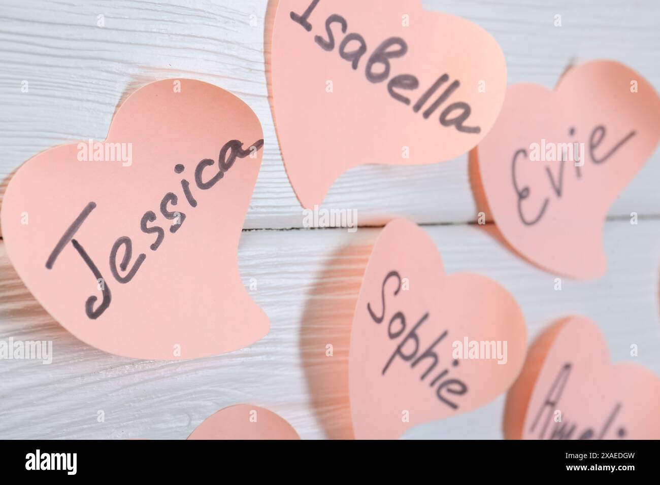 Paper stickers with different names on white wooden table, closeup ...