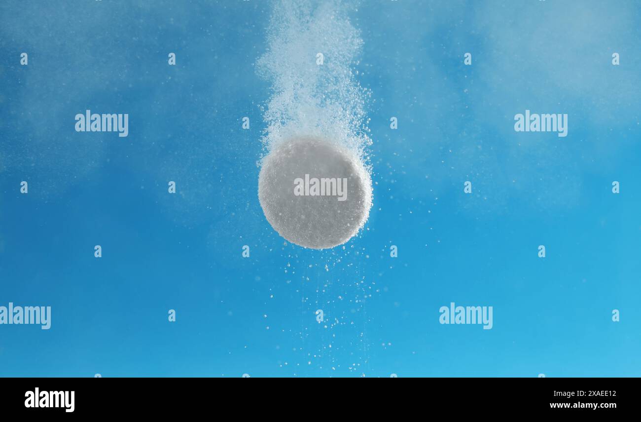 Effervescent pill dissolving in water on light blue background, closeup ...