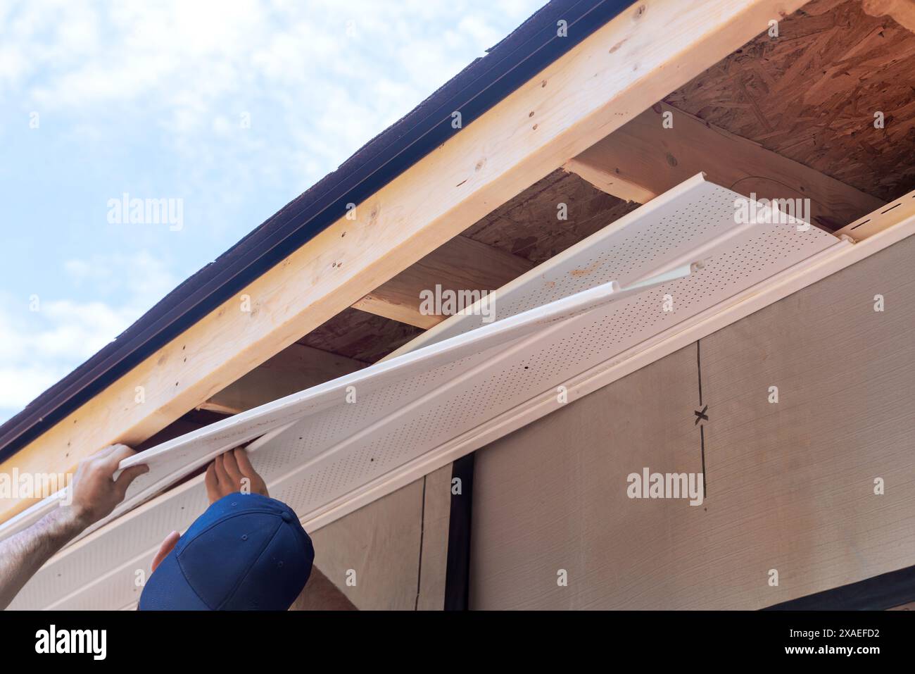 Installation of plastic vinyl soffit at ceiling corner on rafters ...