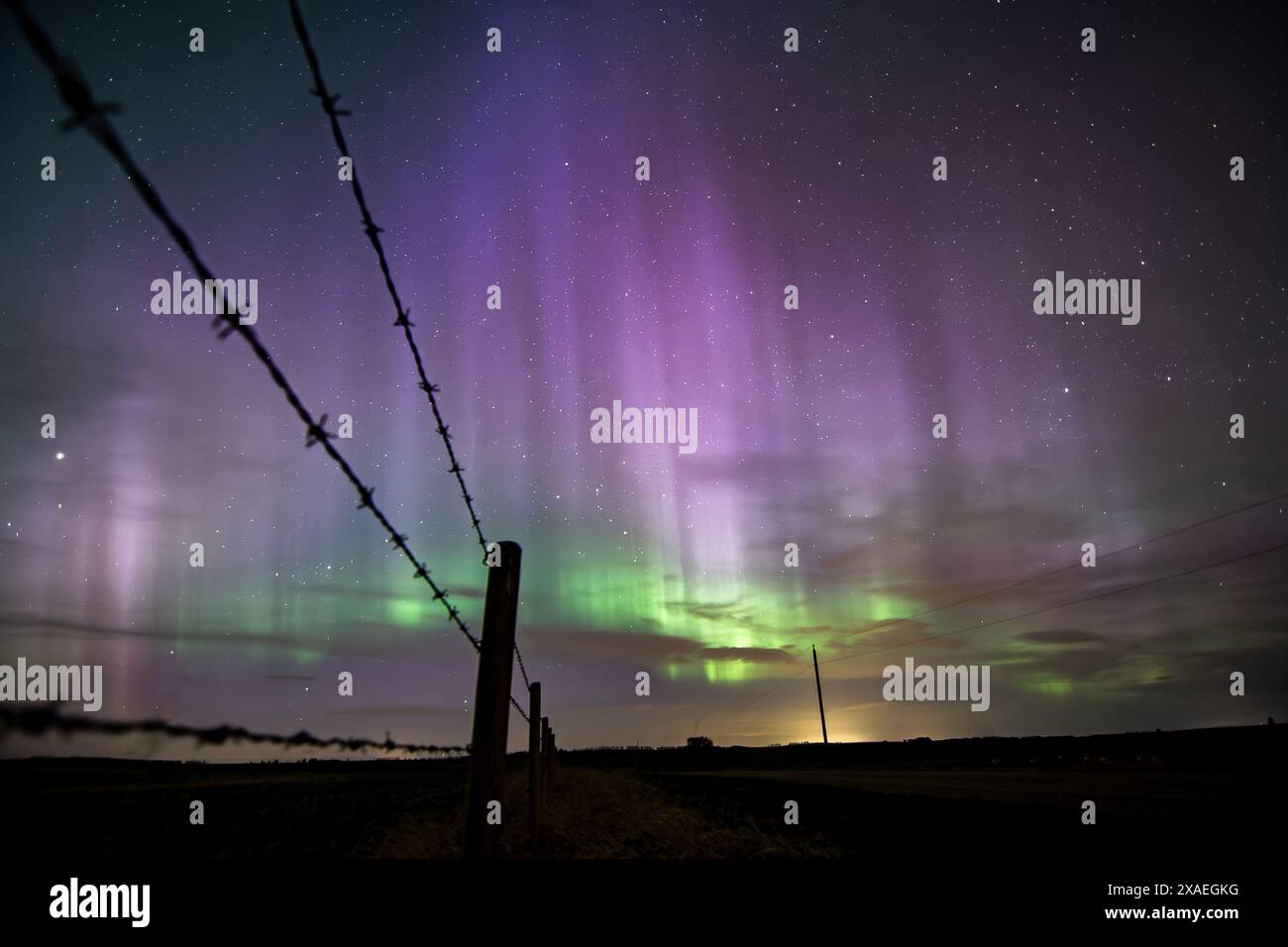 Aurora lights dancing across the night sky with a barbed wire fence ...