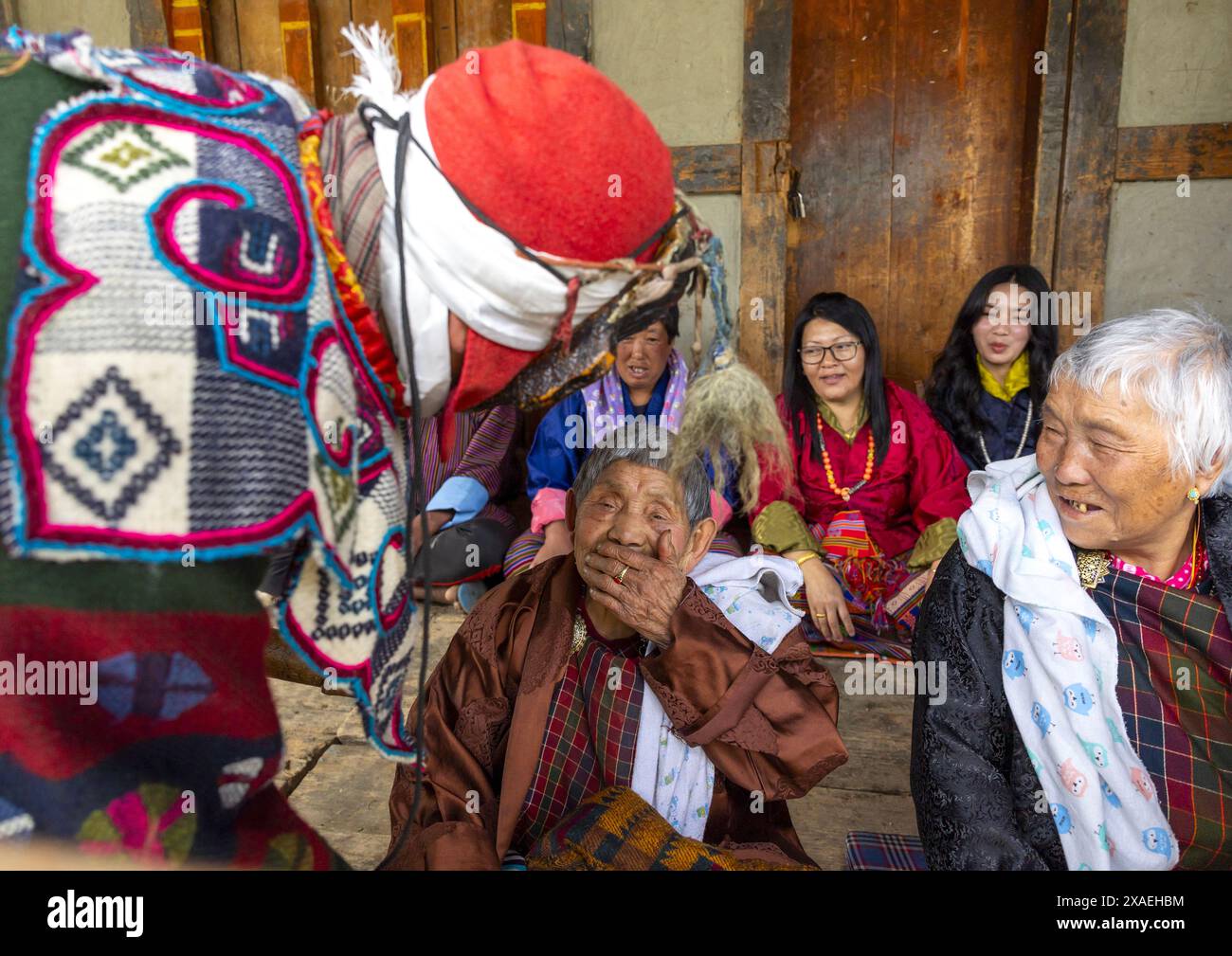 Masked atsara with women at Ura Yakchoe festival, Bumthang, Ura, Bhutan ...