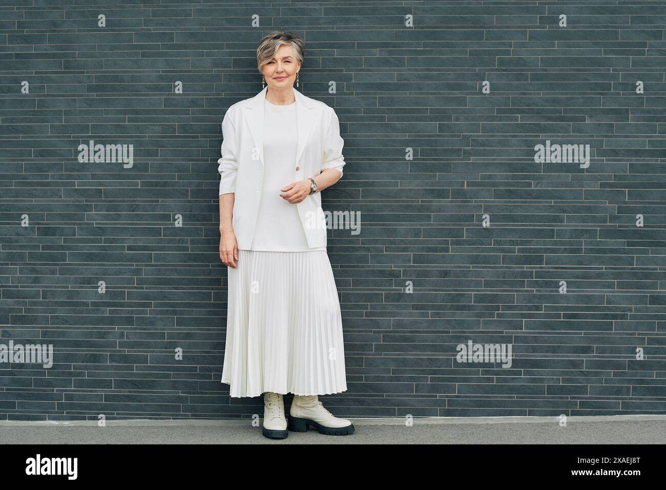 Portrait of 55 - 60 year old woman with grey hair, wearing white jacket ...