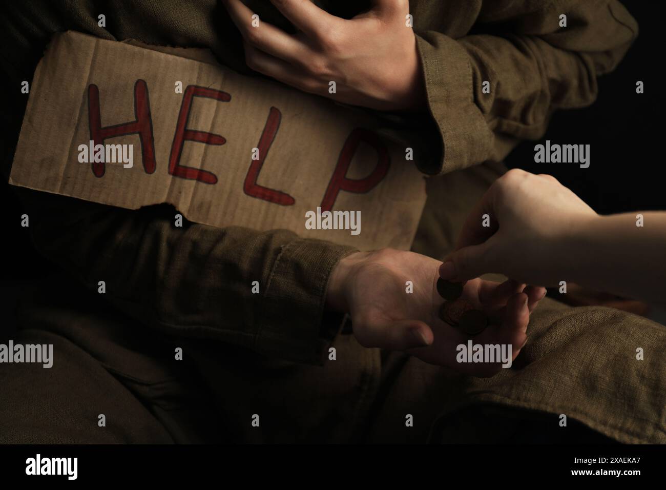 Woman giving coins to homeless with help sign, closeup. Charity and ...