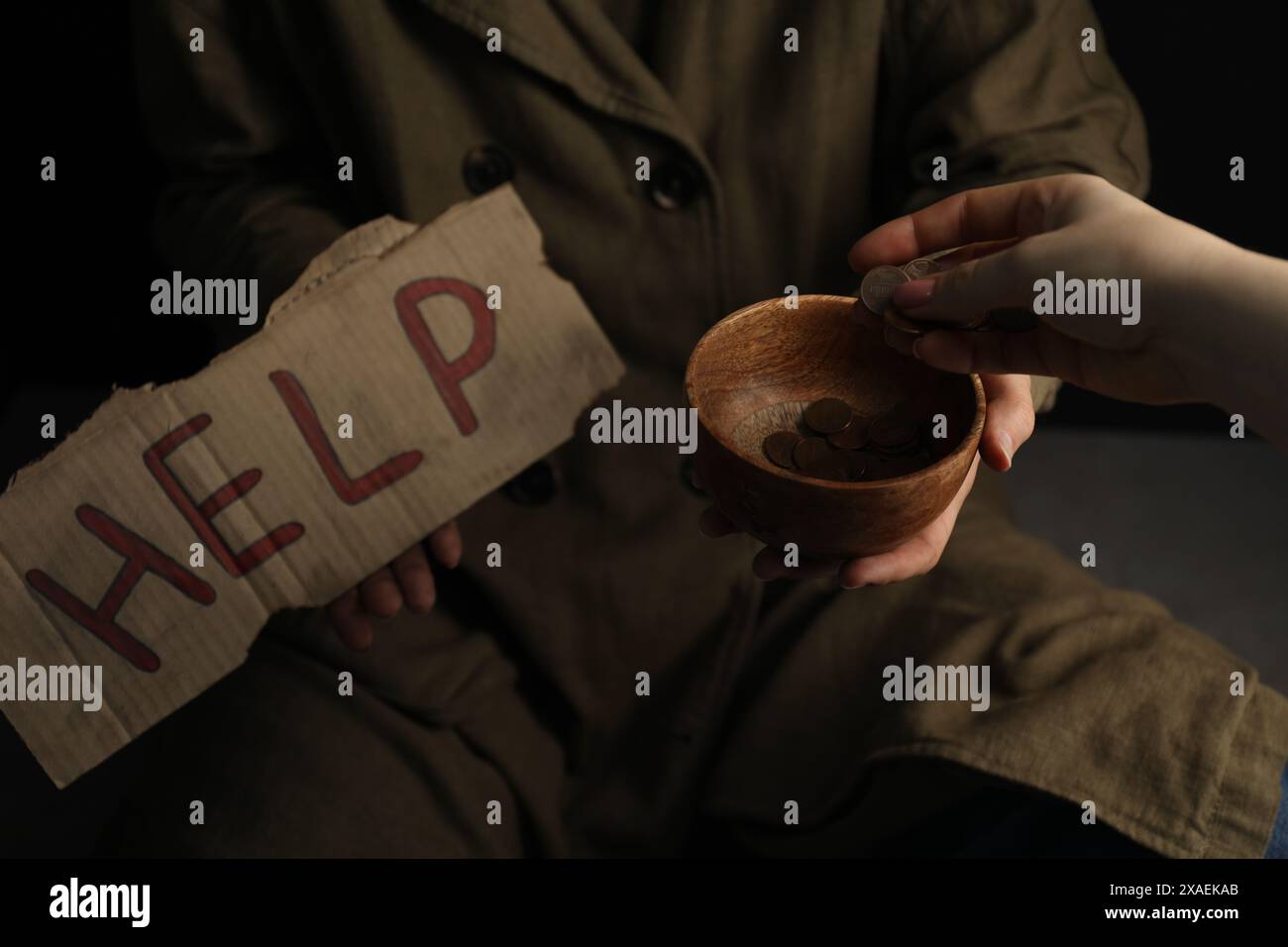 Woman giving coins to homeless with help sign, closeup. Charity and ...