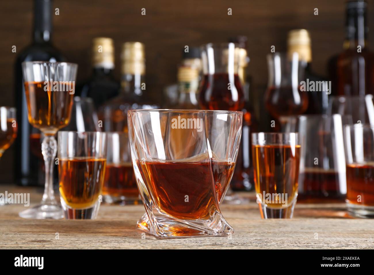Different delicious liqueurs in glasses and bottles on wooden table ...