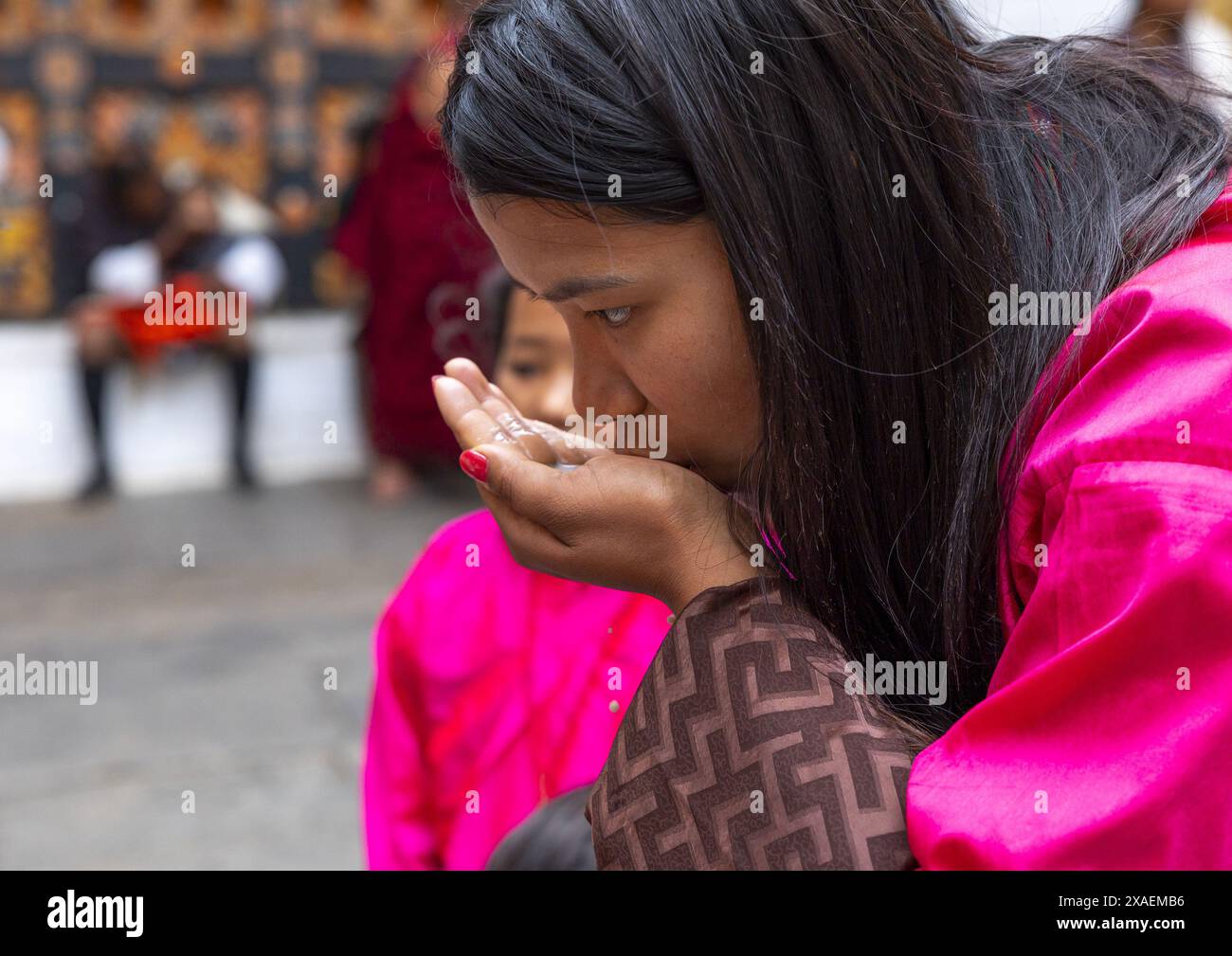 Bhutanese pilgrim eating black lentils with milk in Punakha Dzong ...
