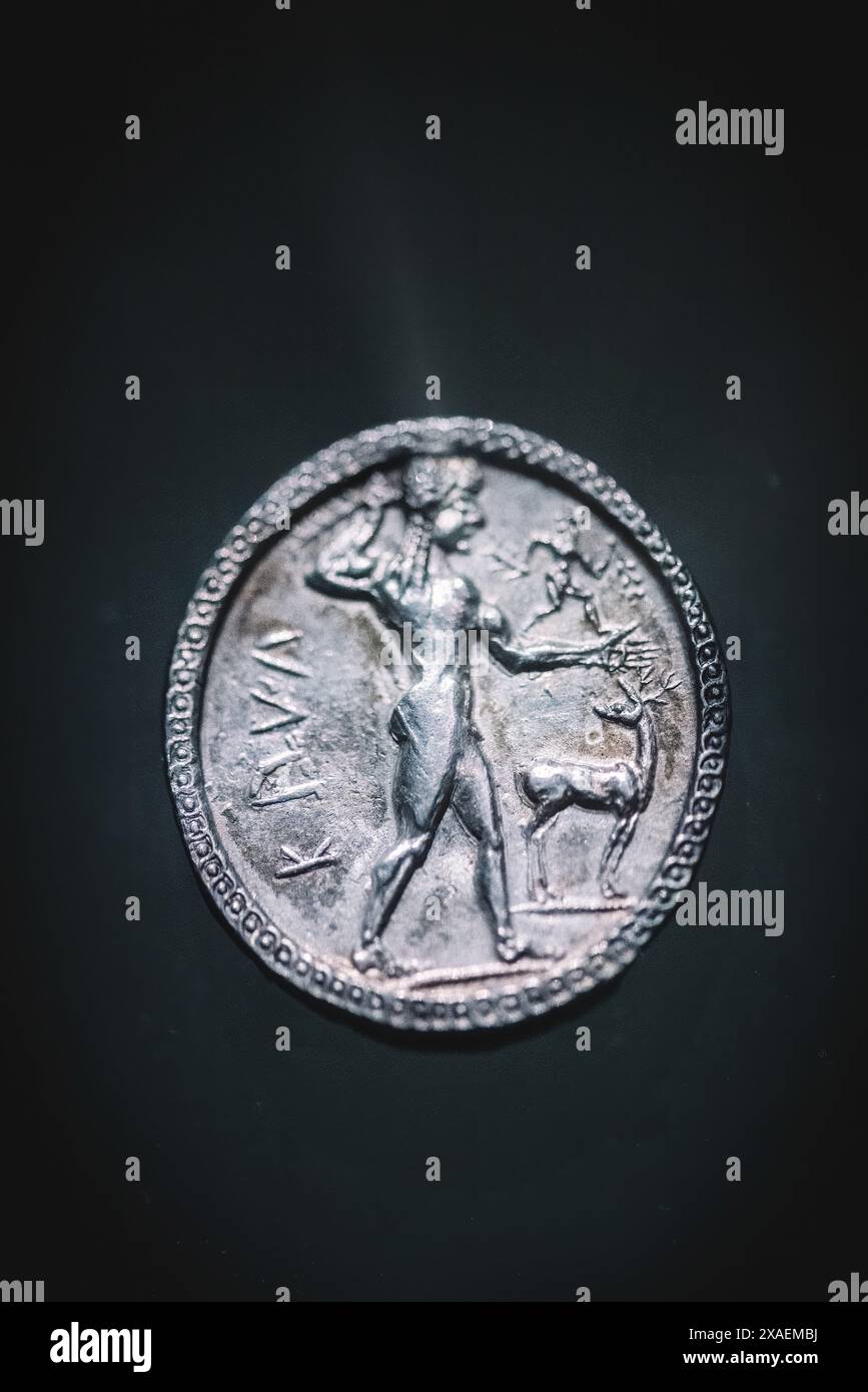 A close-up image of an ancient Greek silver coin. The coin features a ...