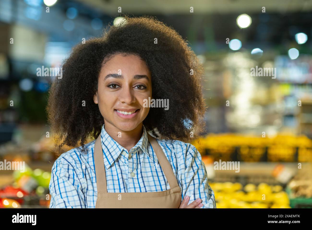 Portrait of a smiling grocery store clerk with afro hair standing ...