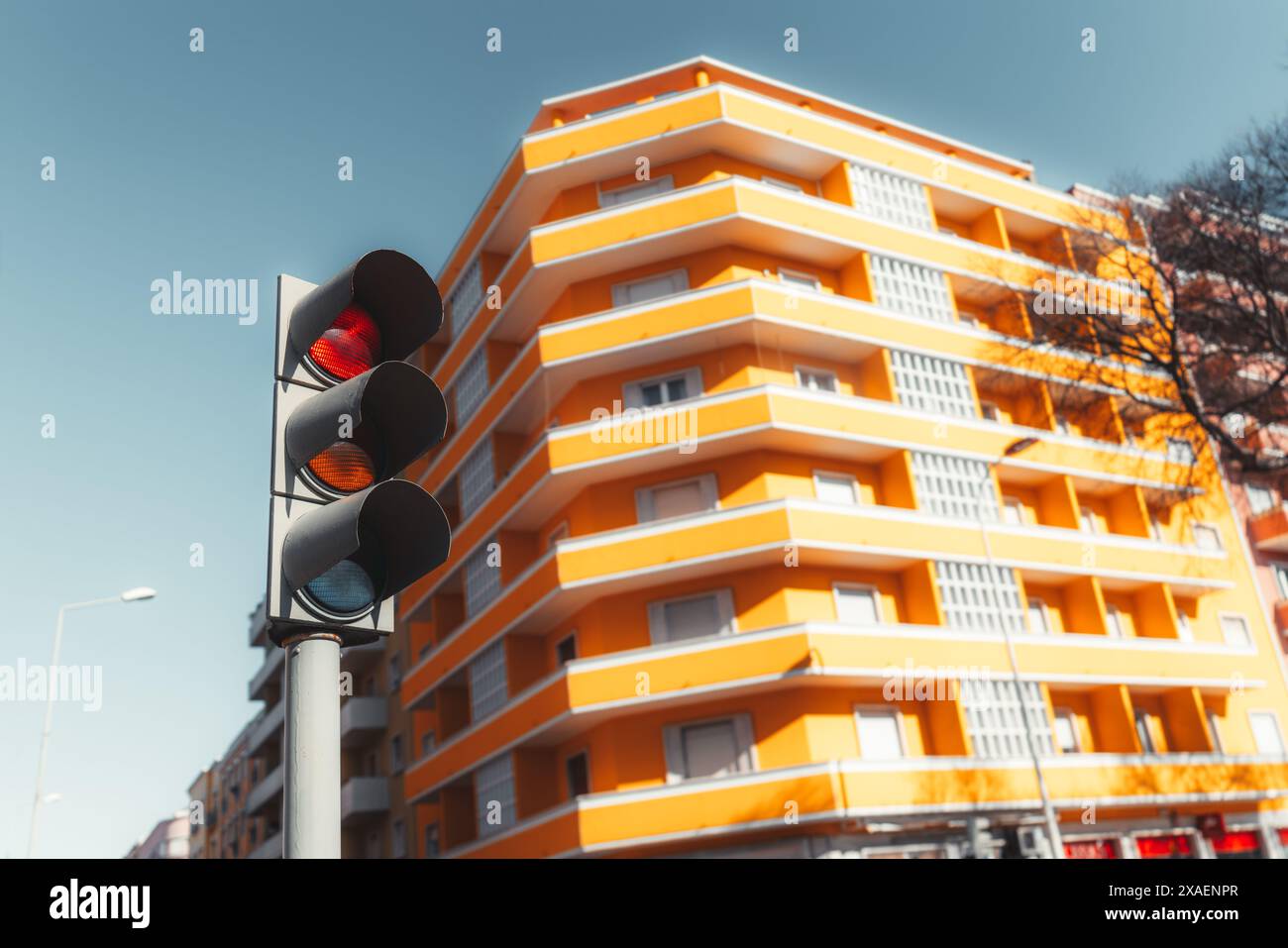 Traffic light showing red signal in front of a modern orange apartment ...